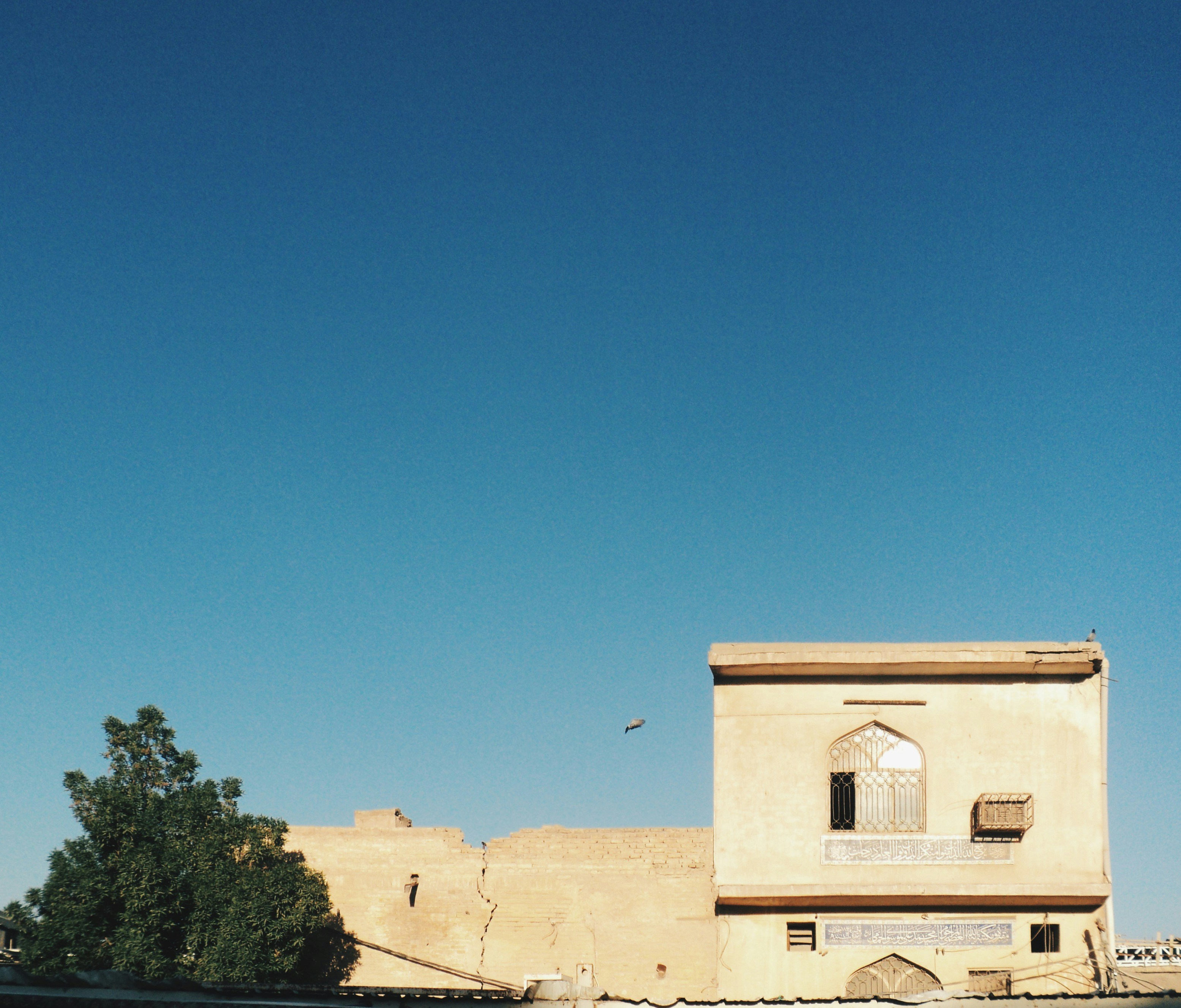 A quiet soul under a boundless sky. | Building with arched windows under a clear blue sky.