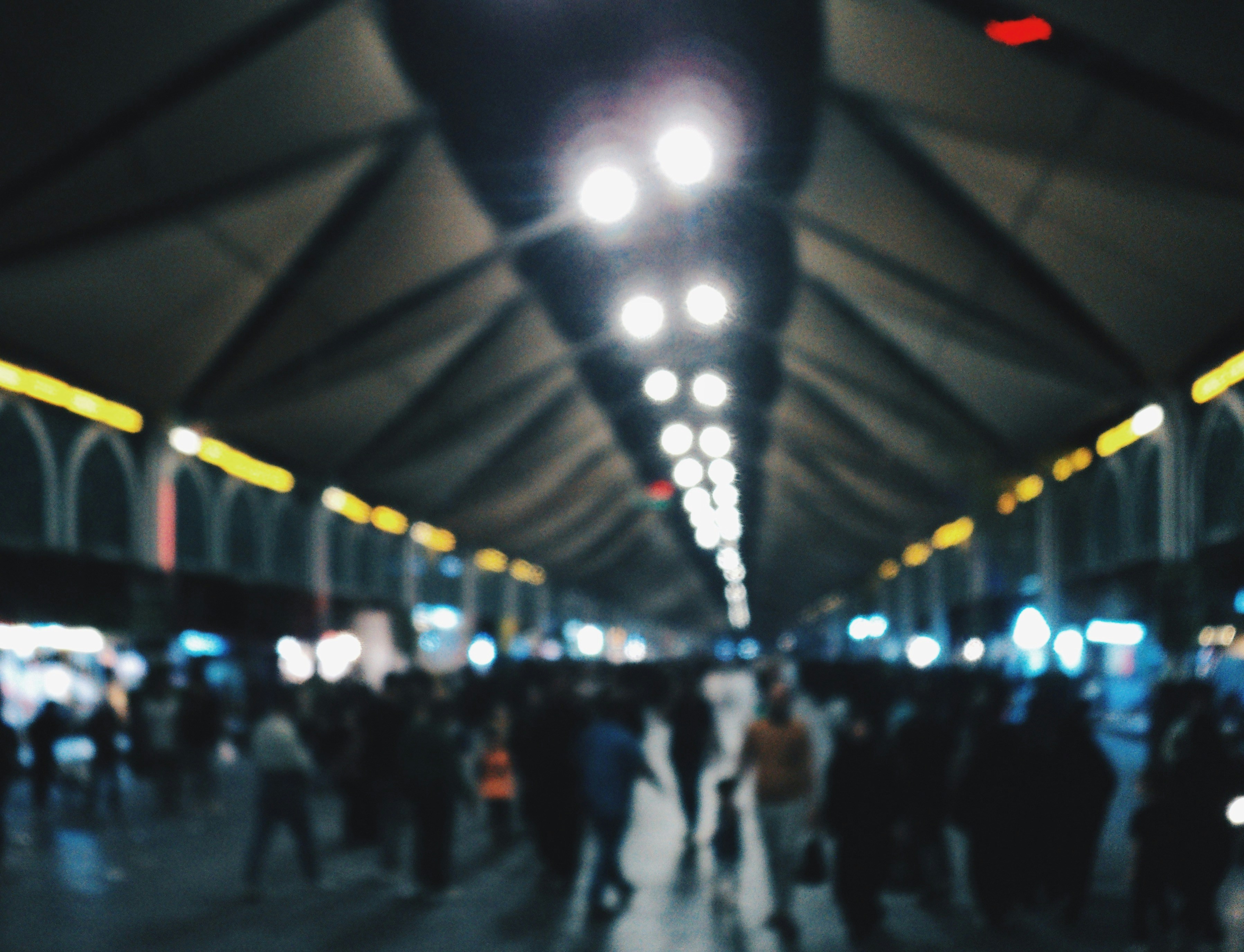 Lost in a sea of light and a thousand souls. | Blurred view of people walking in a large hall