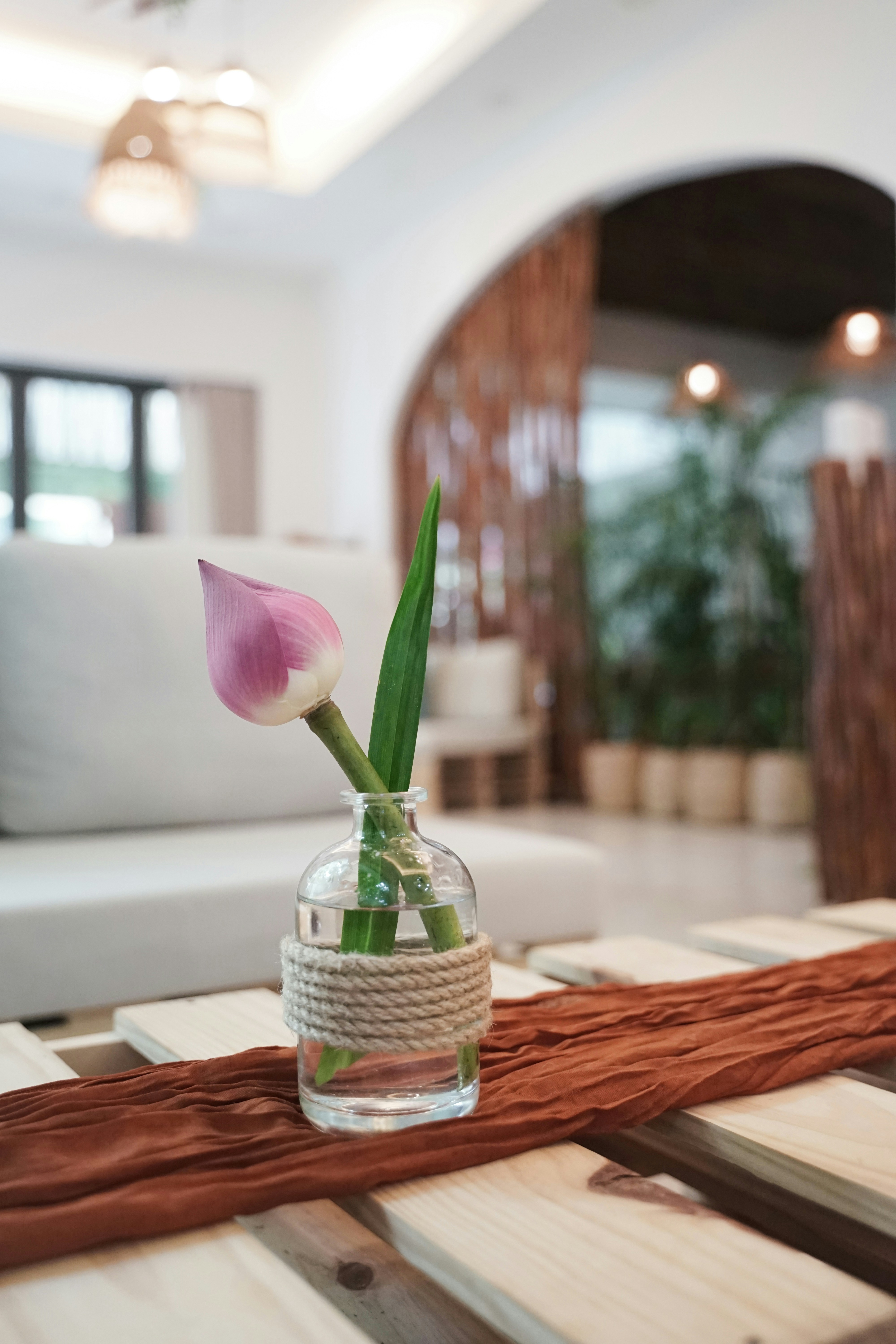 Pink lotus flower in glass vase on wooden table