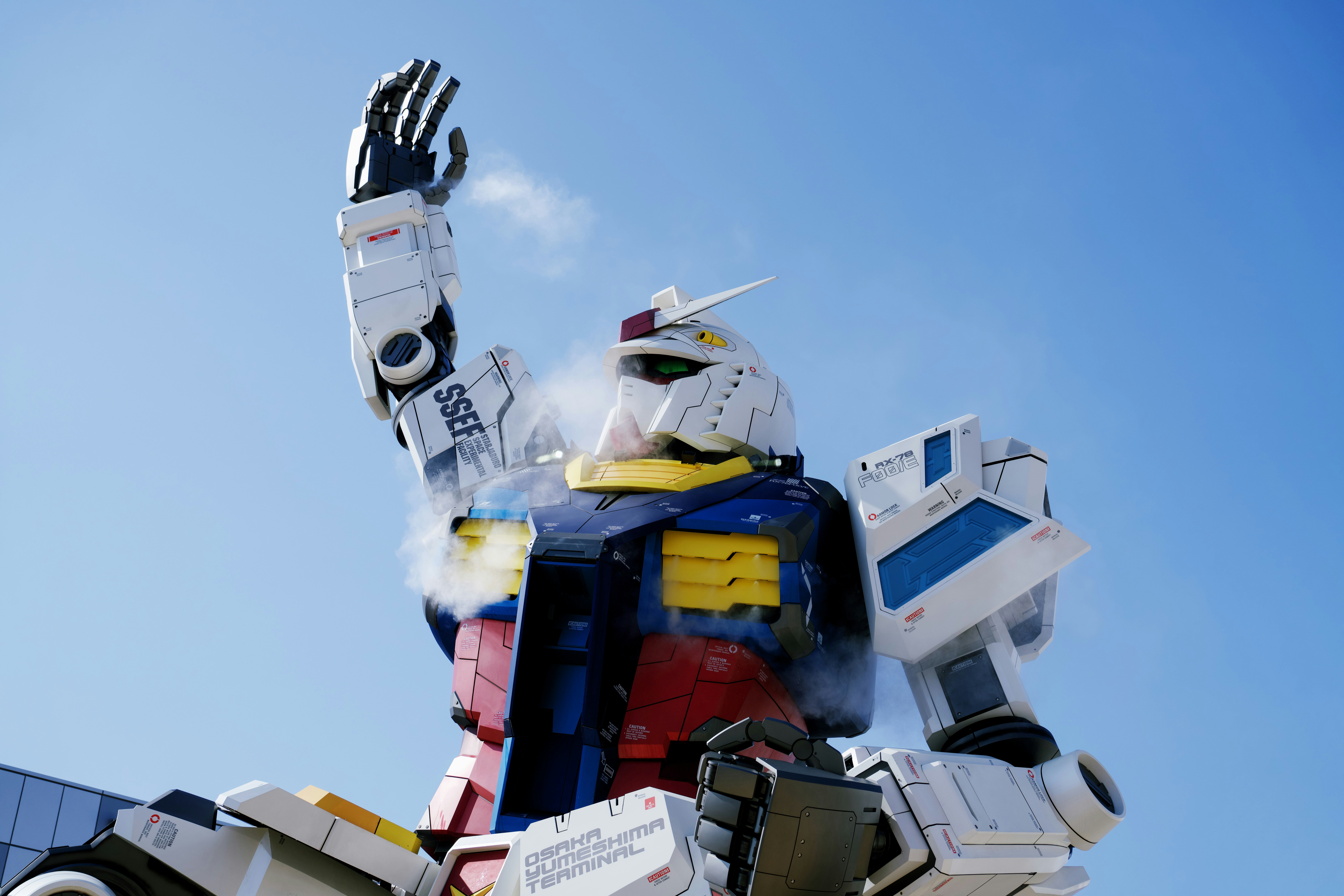 Giant white robot with blue and red accents waves.