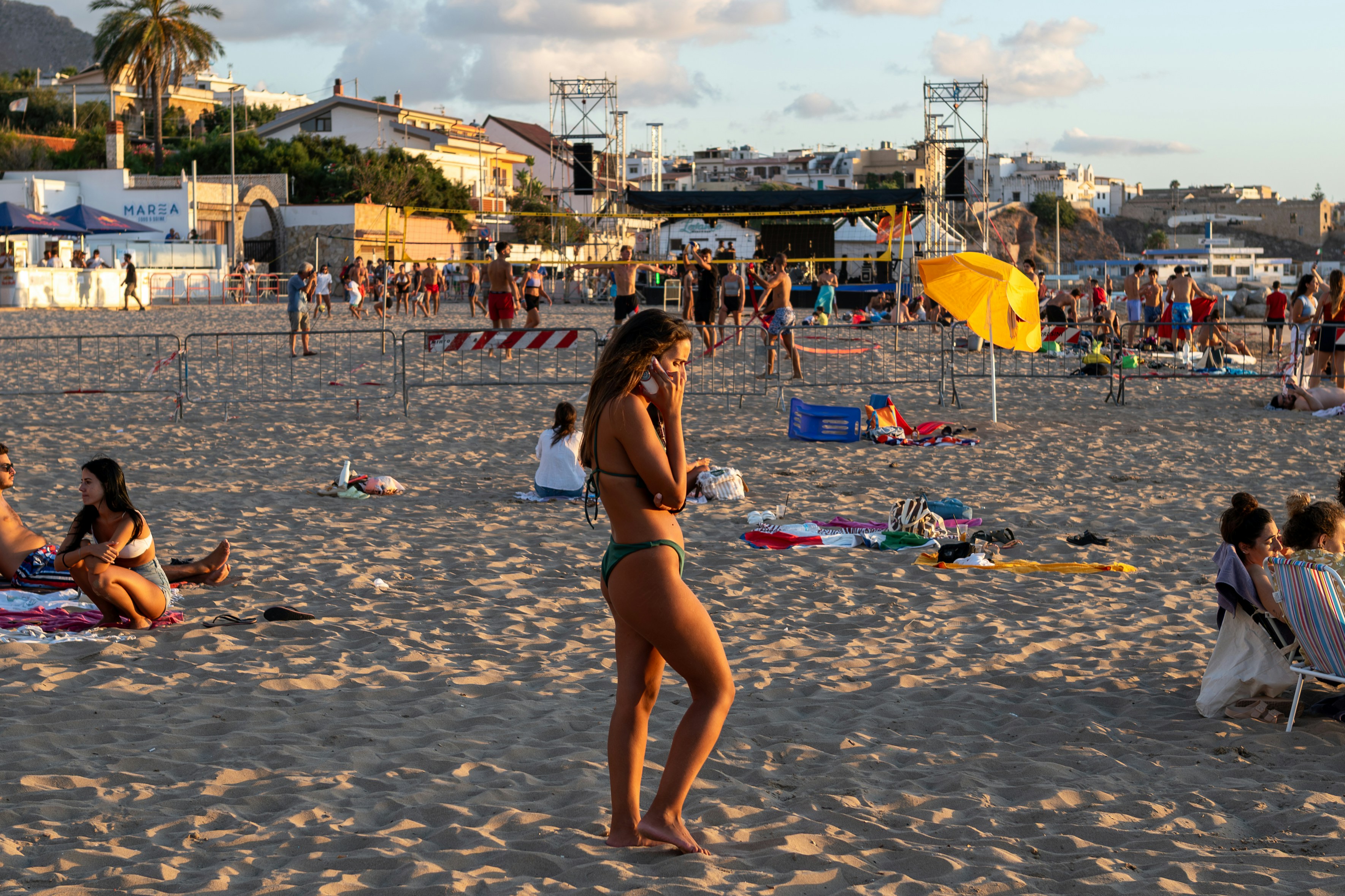 Woman in bikini on a crowded beach at sunset