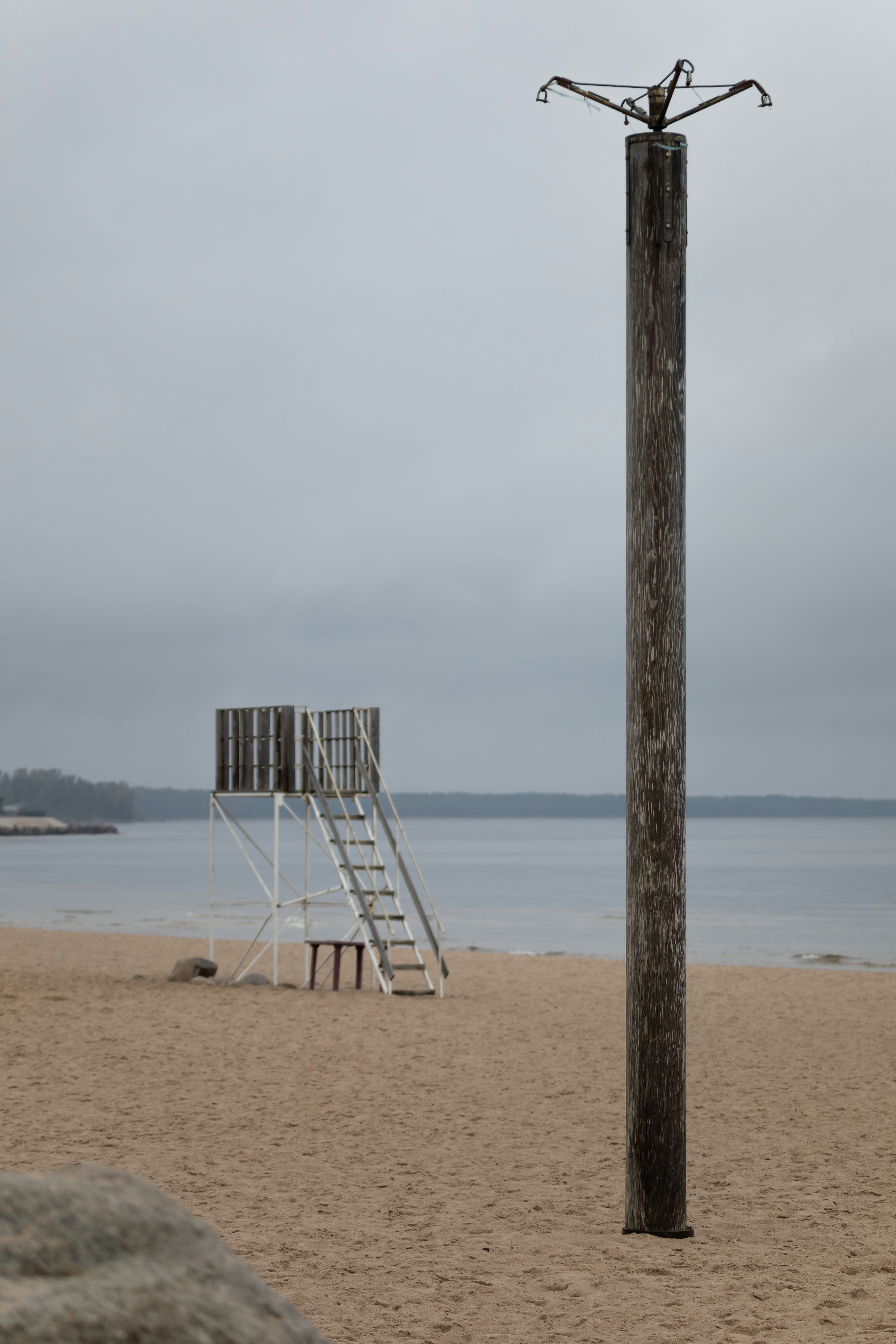 Sentinel on the Shore: Weathered Pole Over a Quiet Beach