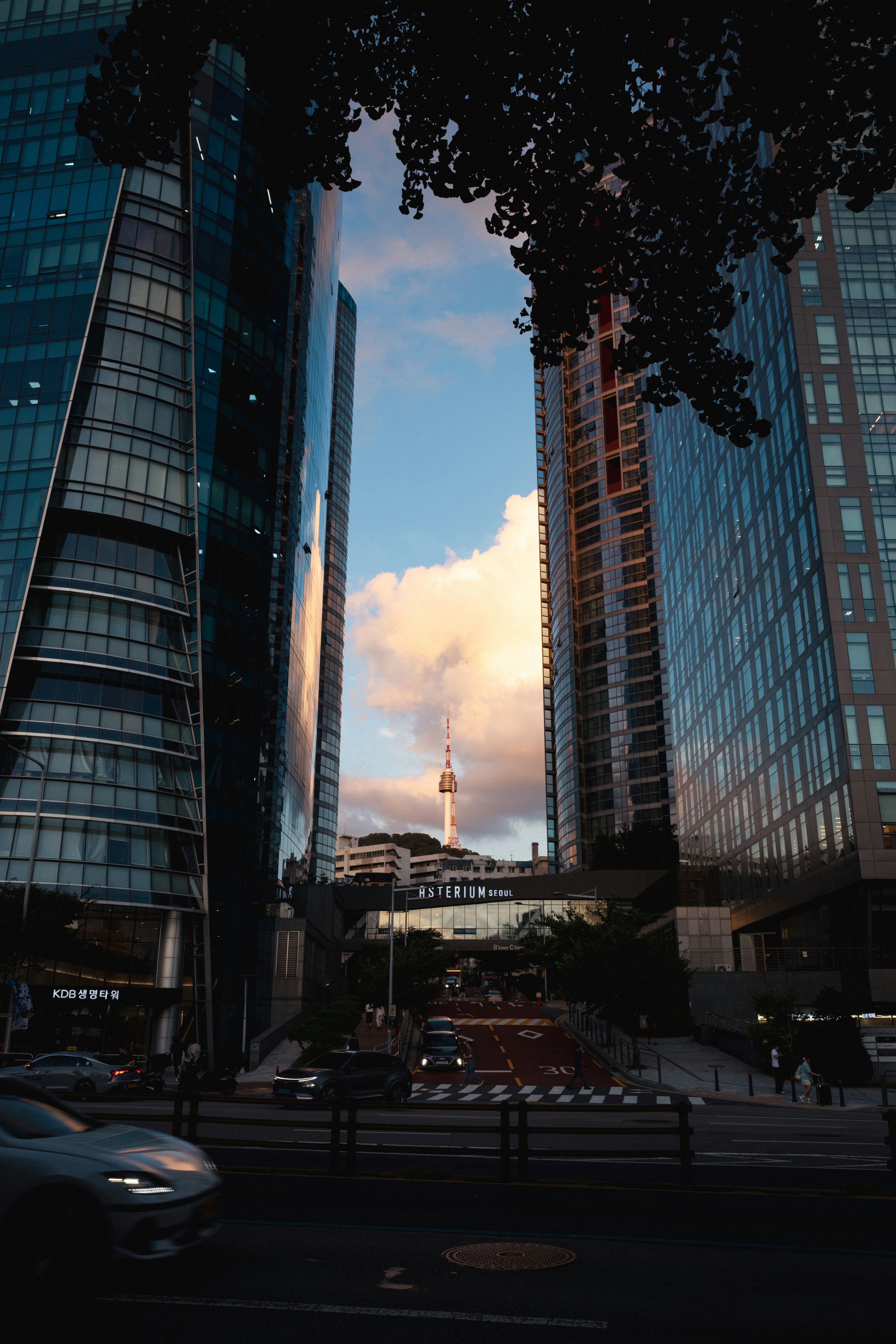 Modern skyscrapers frame a distant tower under a cloudy sky.