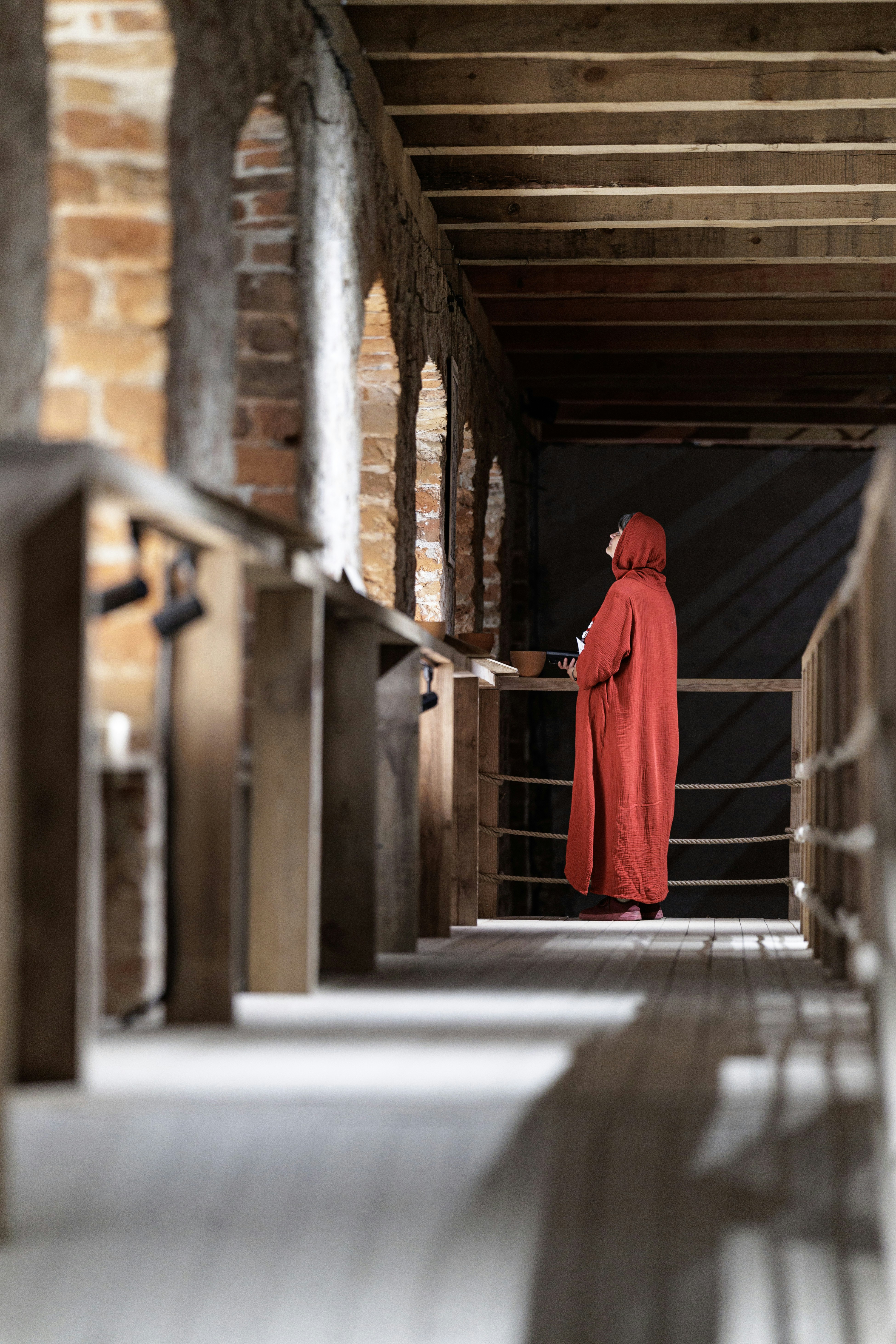 Person in red robe looking out from castle walkway.