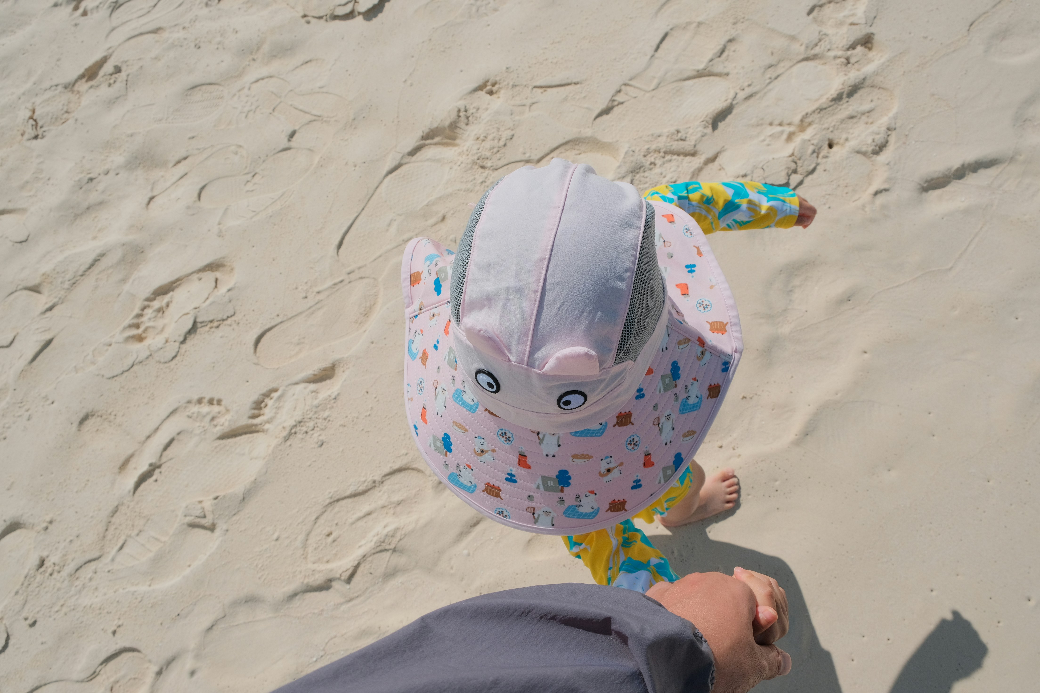 Child wearing a sun hat on a sandy beach