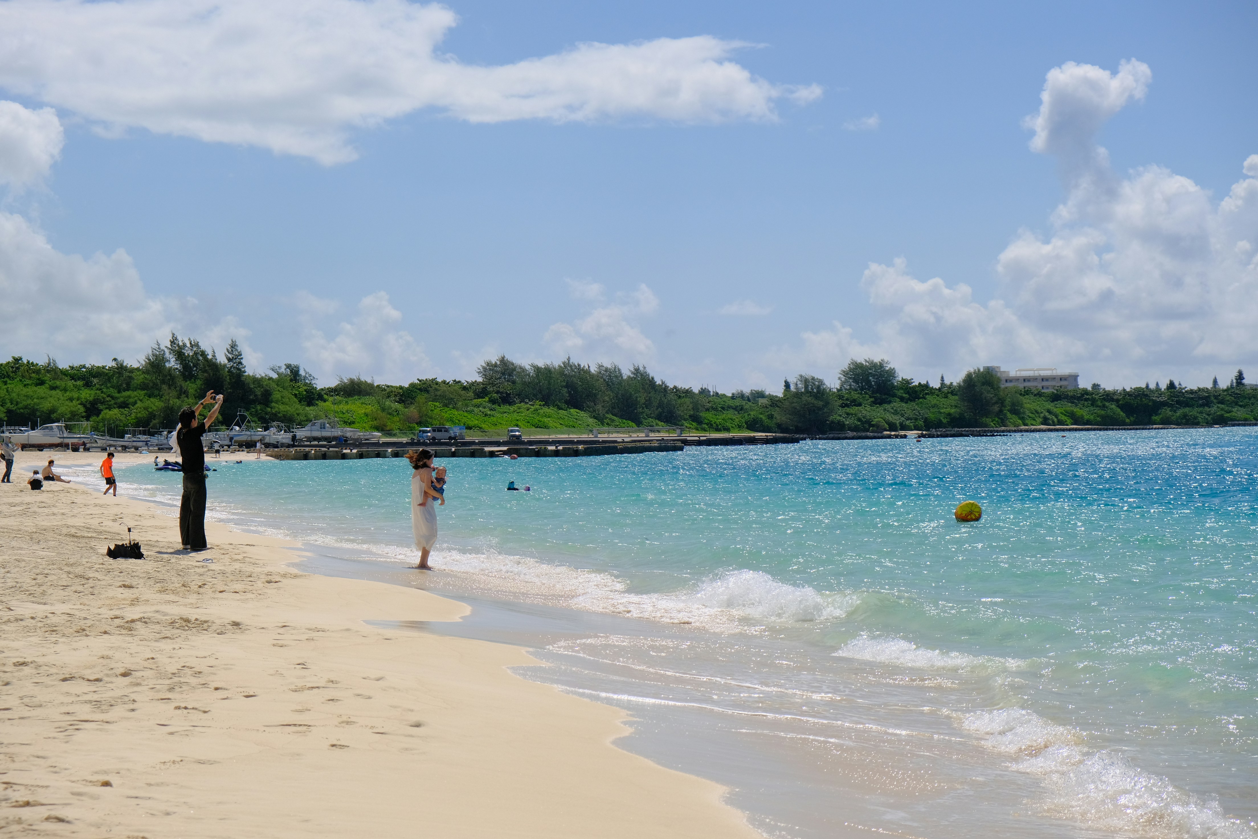 People relaxing on a sandy beach with turquoise water.
