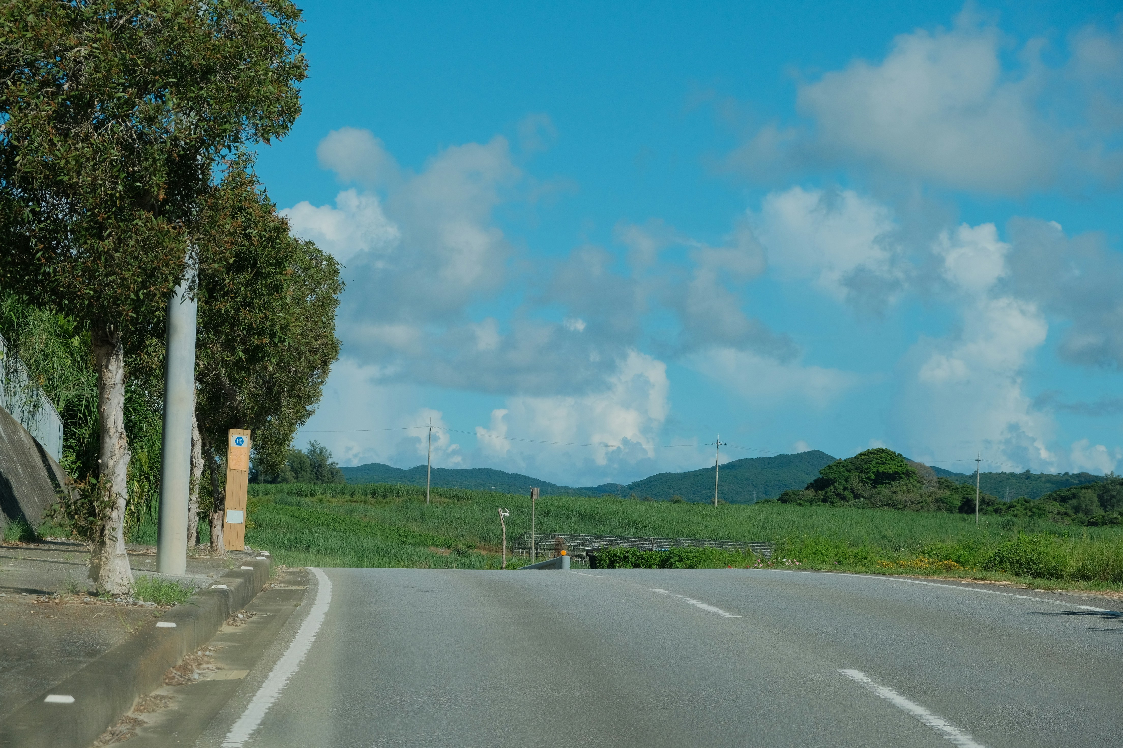 Empty road with green fields and blue sky