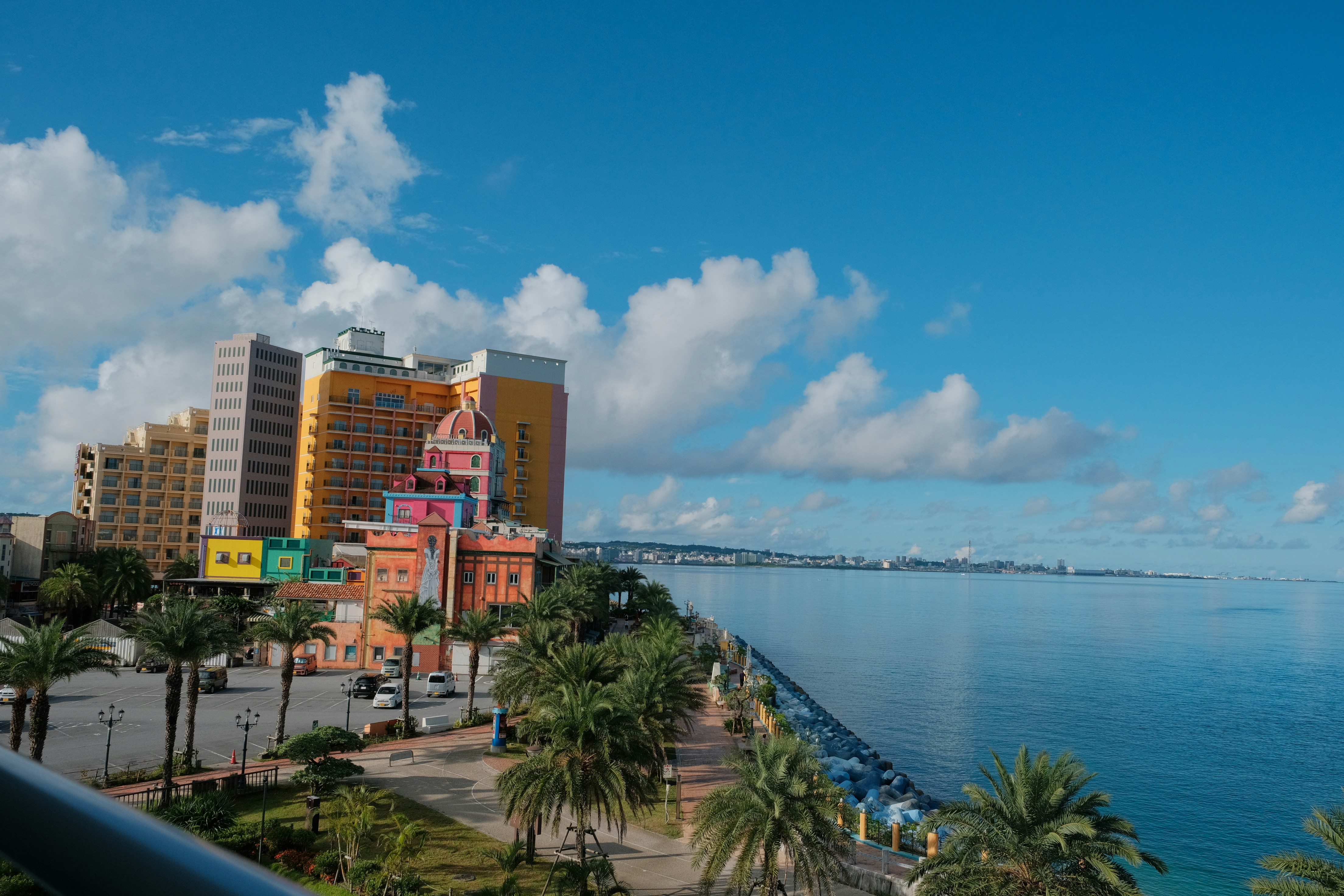 Colorful buildings along a calm blue ocean under a cloudy sky.