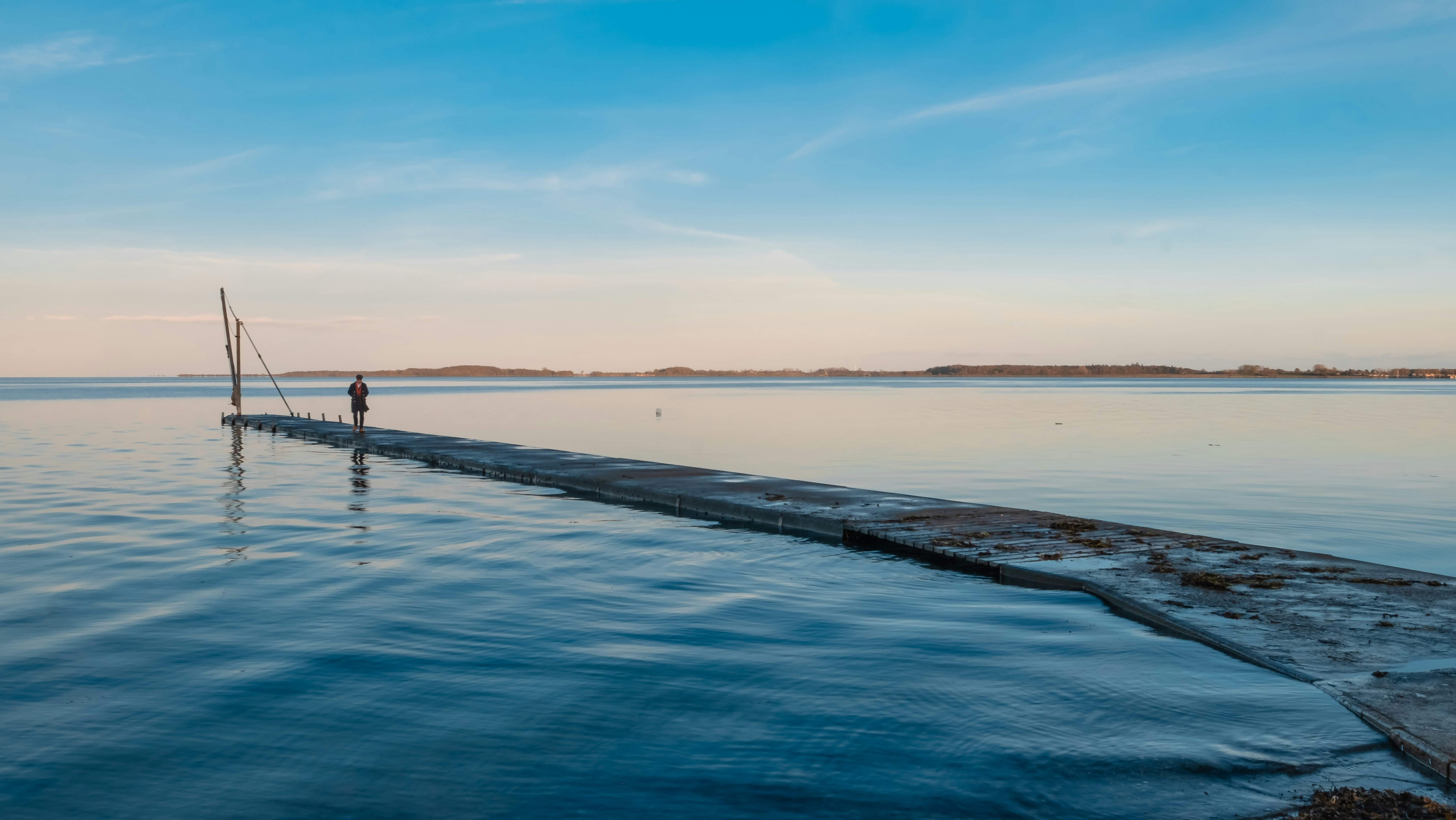 Person standing on a pier at sunset