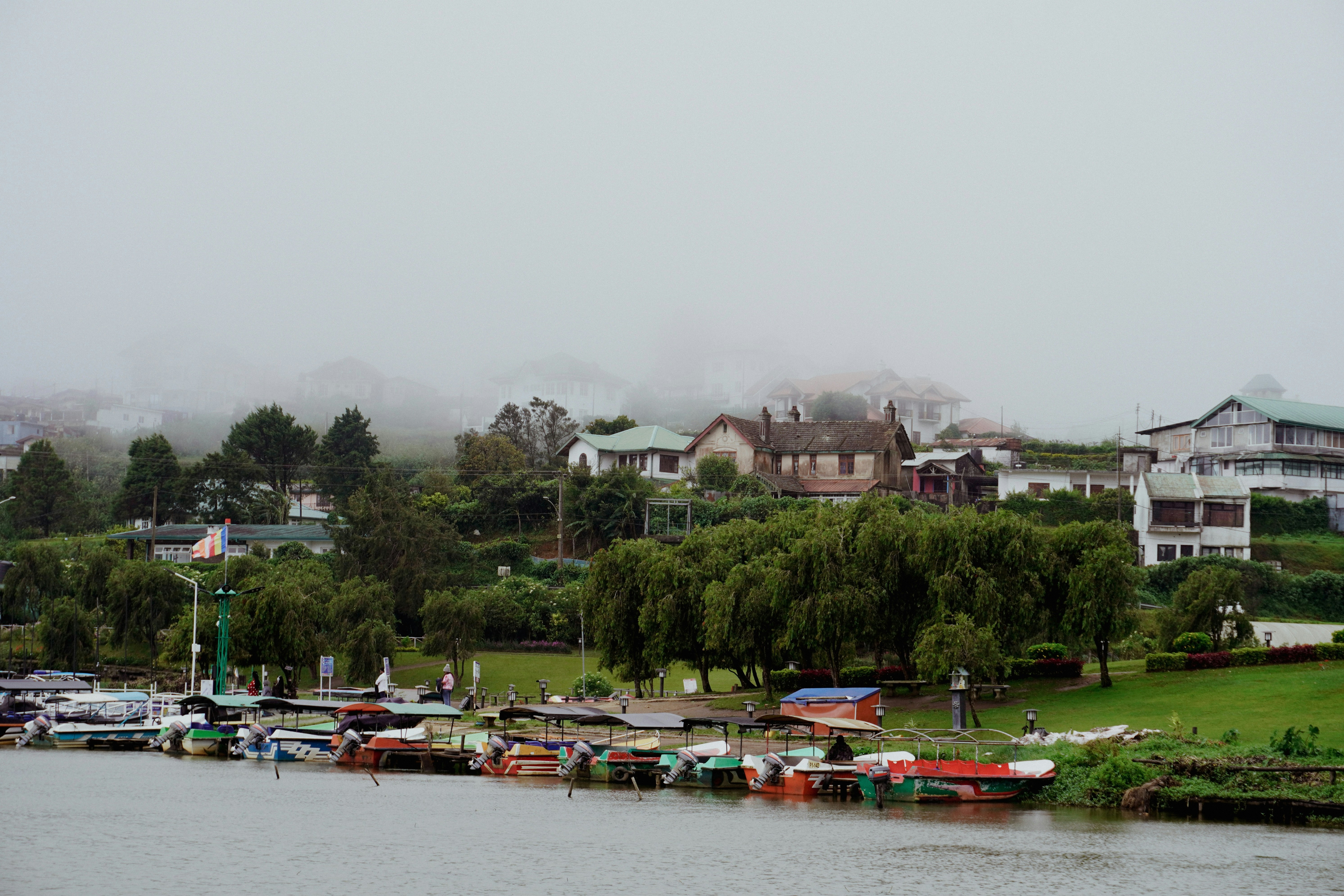 Lake Gregory, Nuwara Eliya, Sri Lanka | Boats docked by a misty lakeside town with green hills.