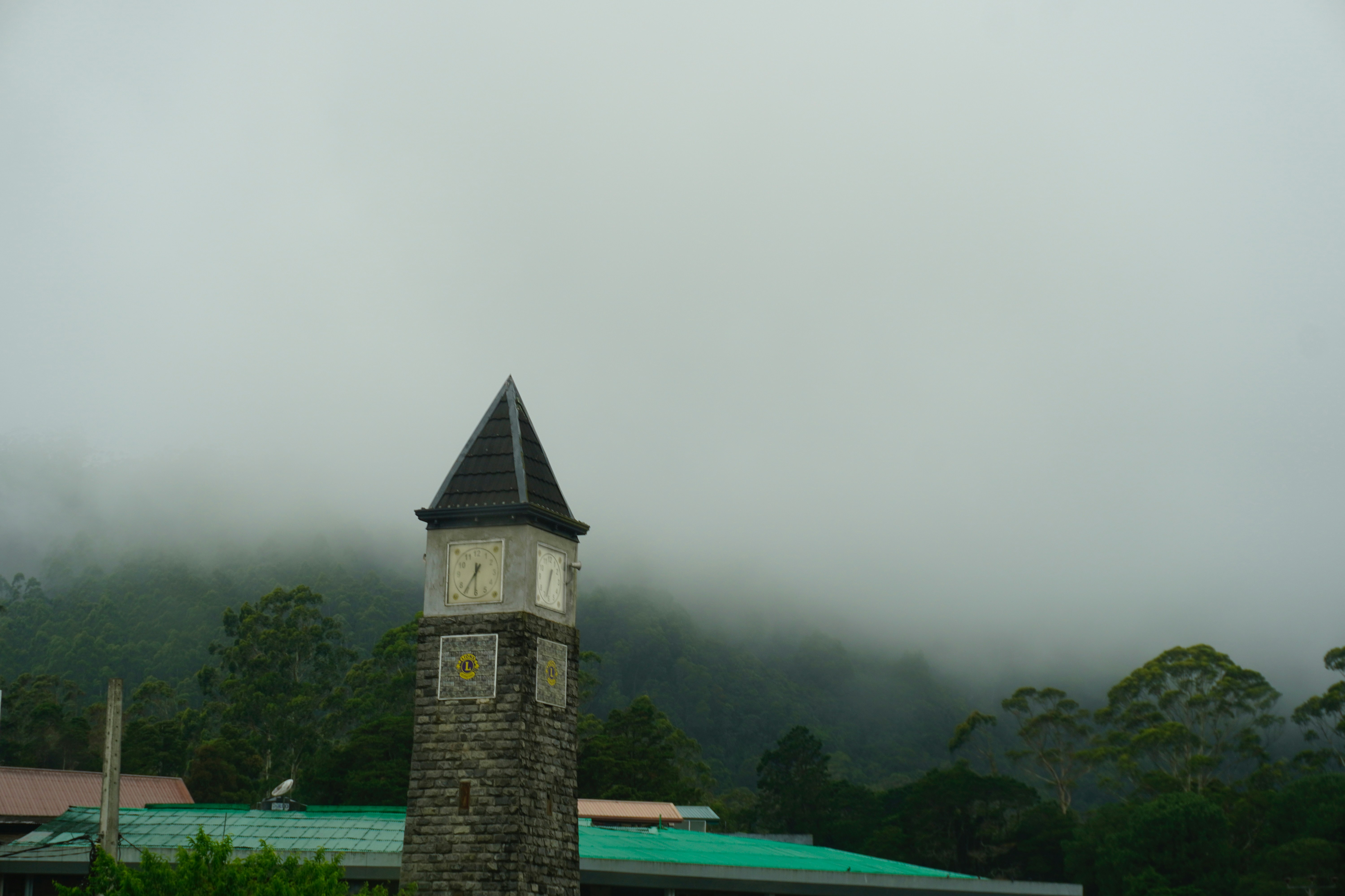 Nuwara Eliya, Sri Lanka | Stone clock tower in a foggy, forested landscape.