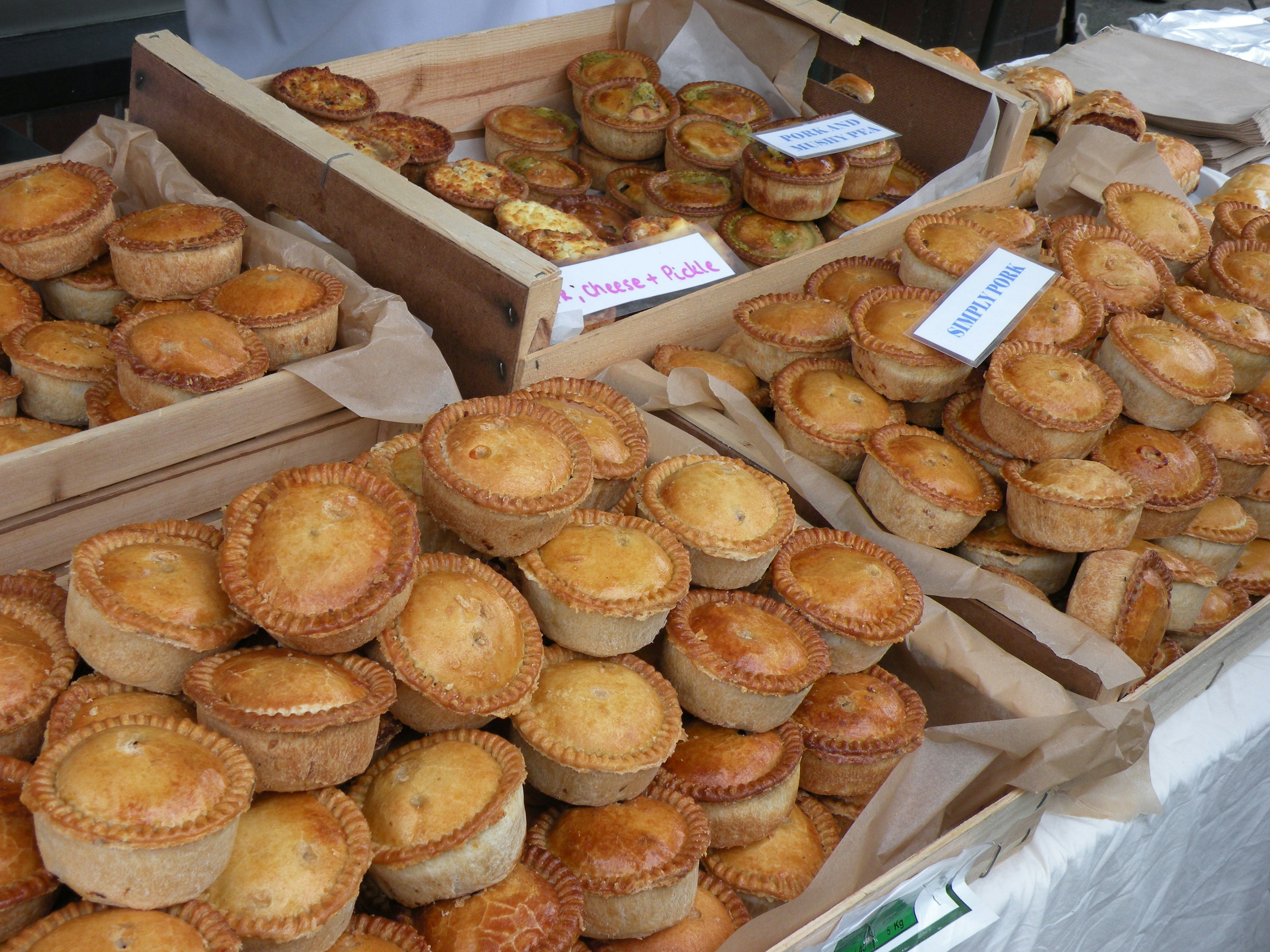 Pork pies at Brighouse food festival | Assortment of small pies in wooden crates at market
