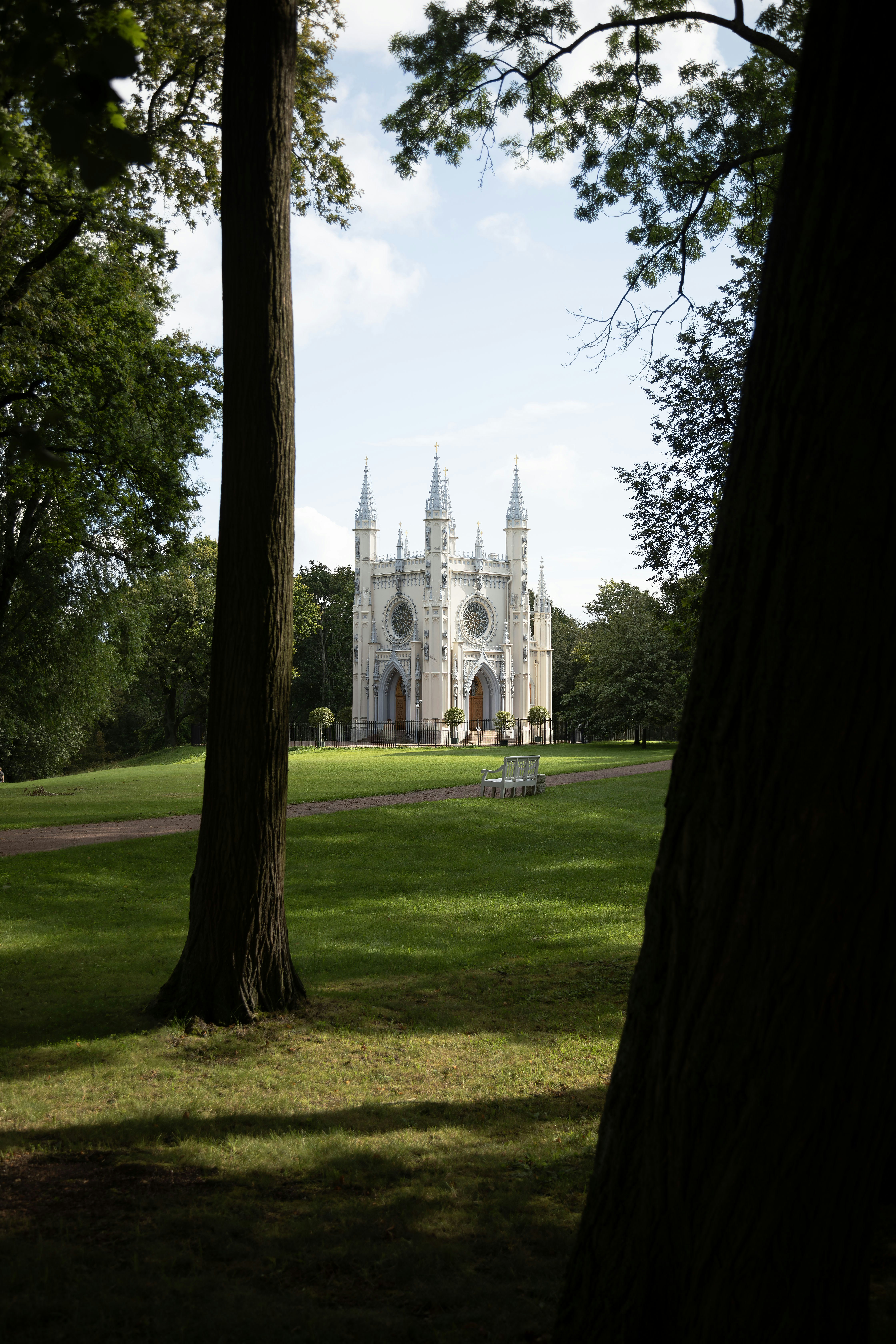 A gothic-style structure framed by towering trees in a lush park setting, inviting contemplation and wonder.