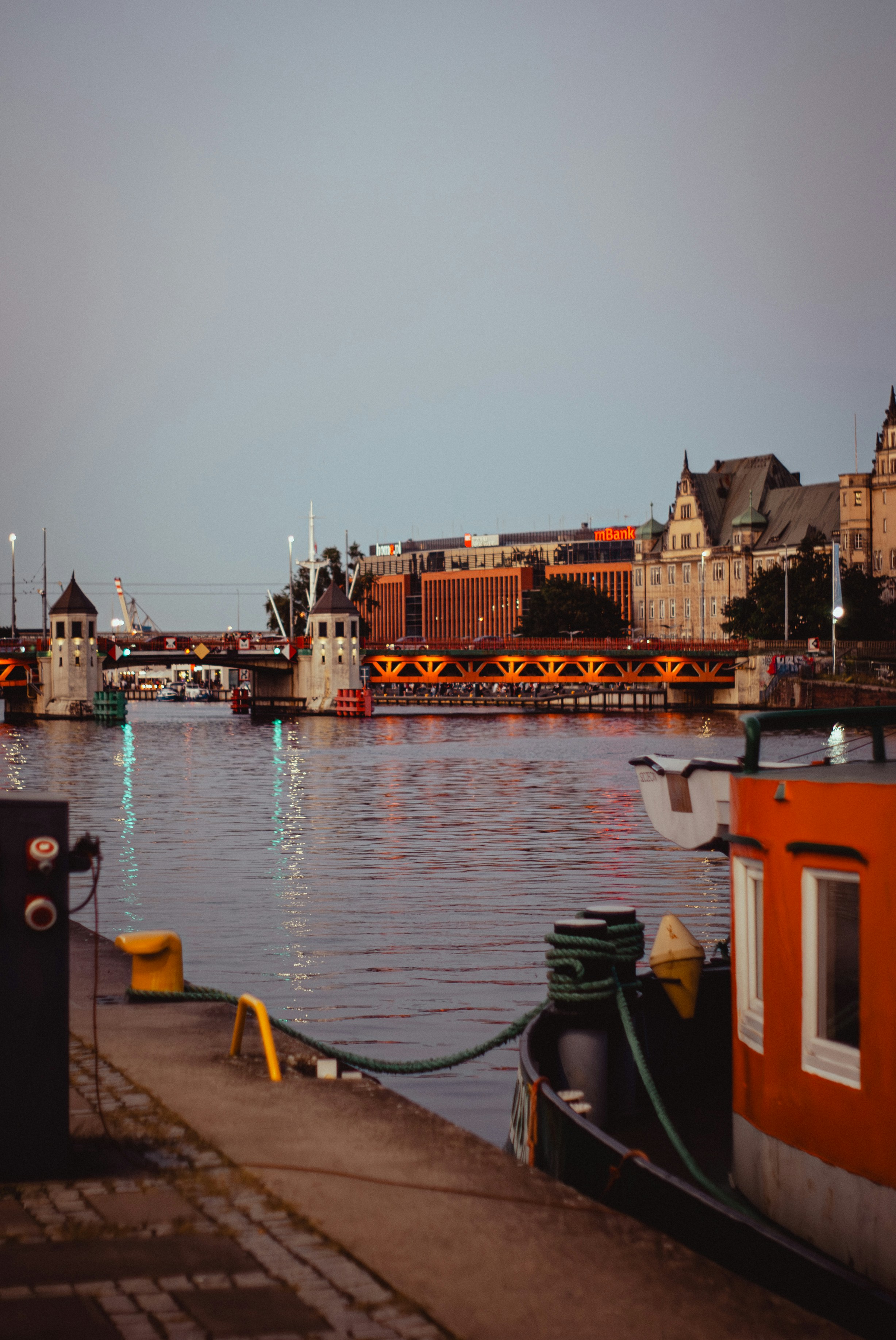 City skyline with a river and boats at dusk.