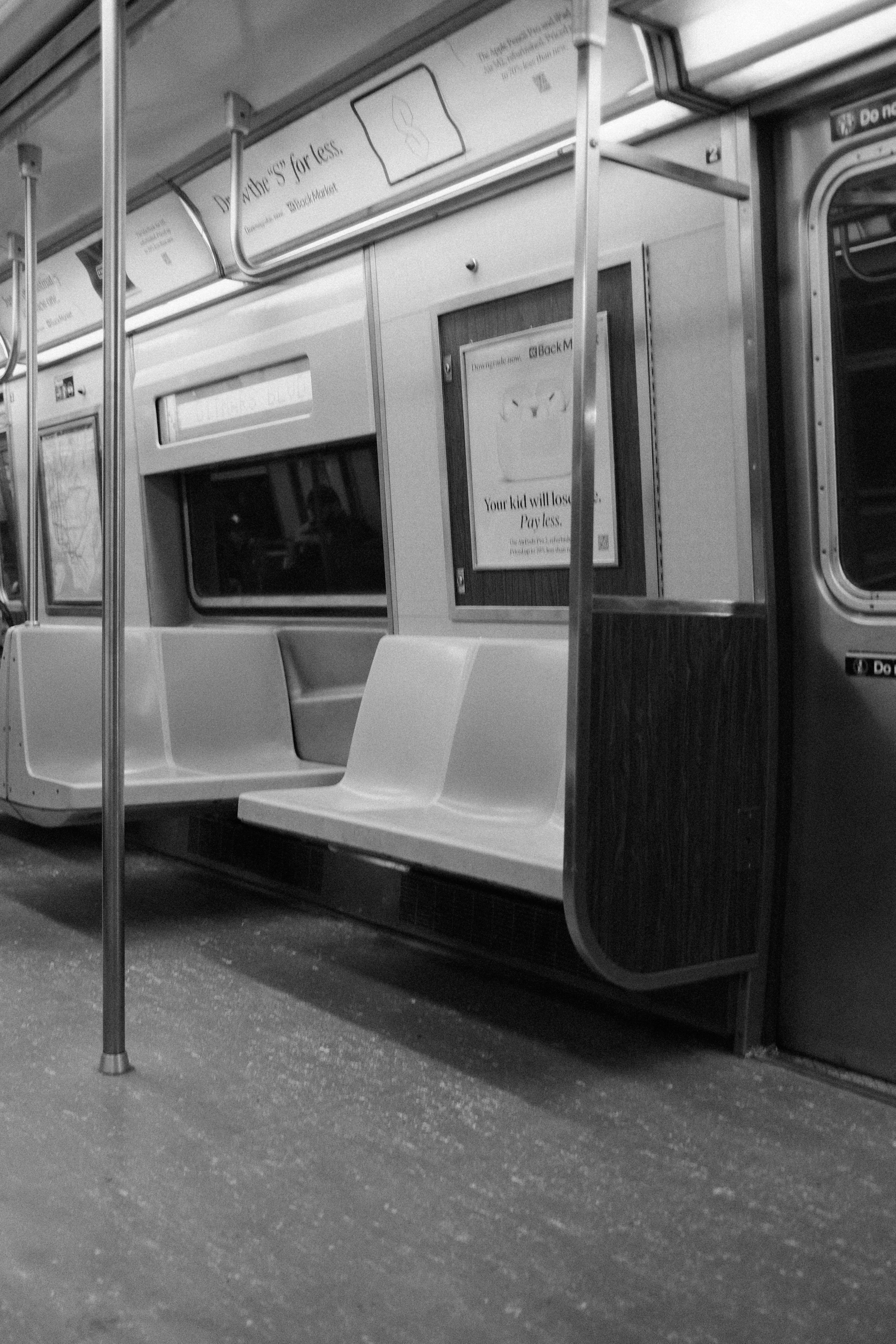 Empty subway seats and poles in black and white.
