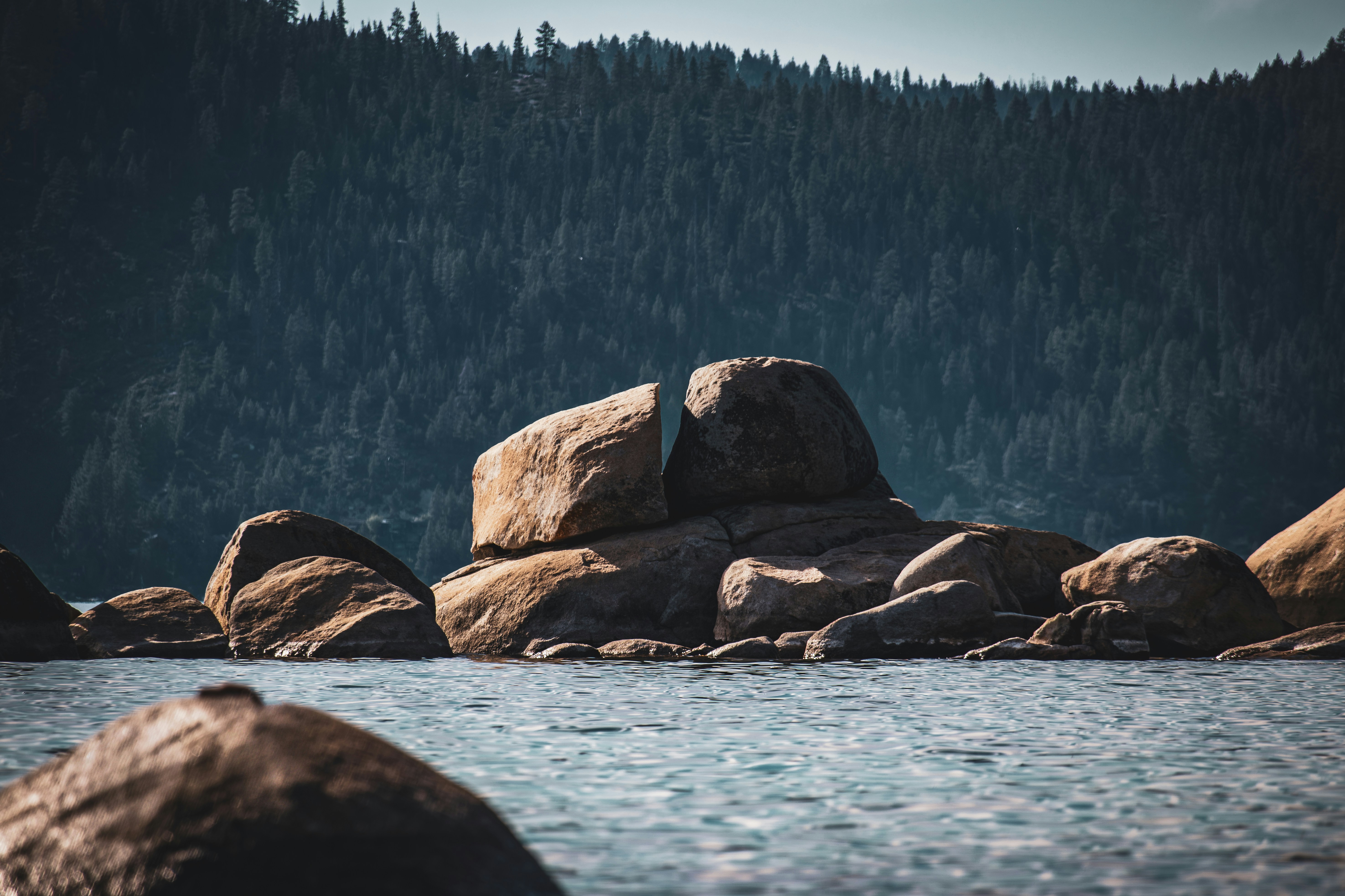 Large rocks in a calm lake with forest background