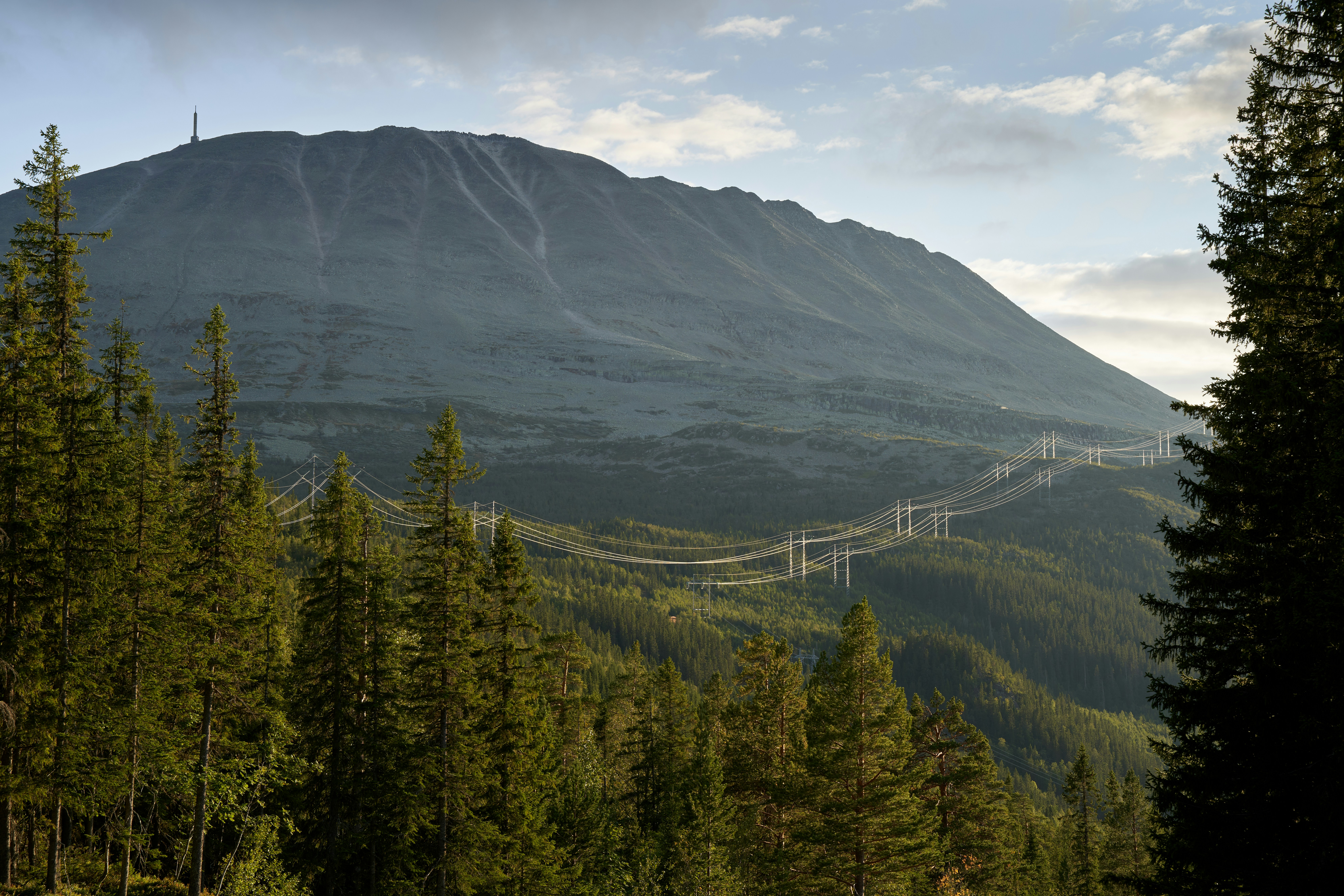 The Silent Sentinel: Power Lines Stretching Across the Mountain's Base