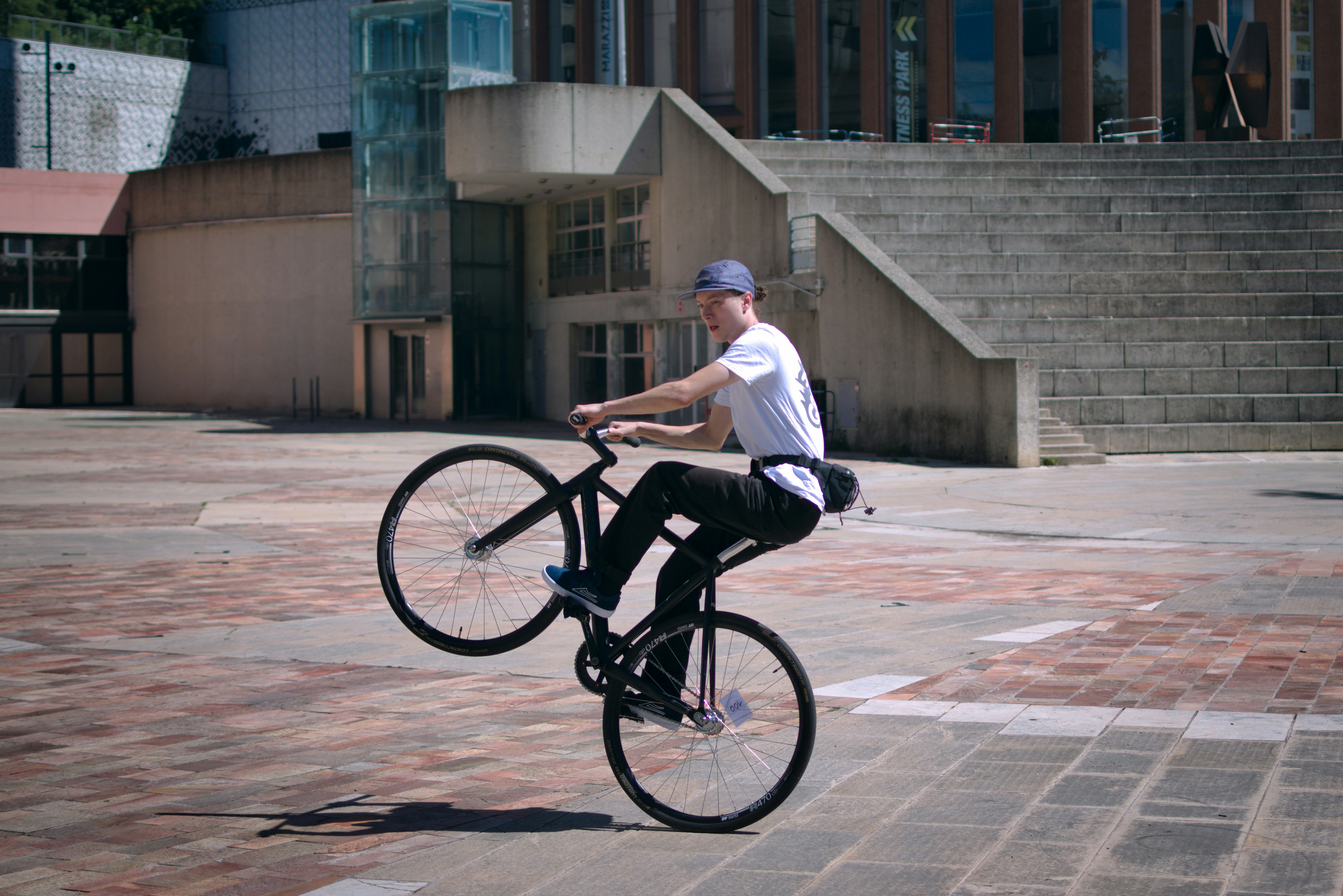 Man performing a wheelie on a bicycle outdoors photo – Free City Image ...