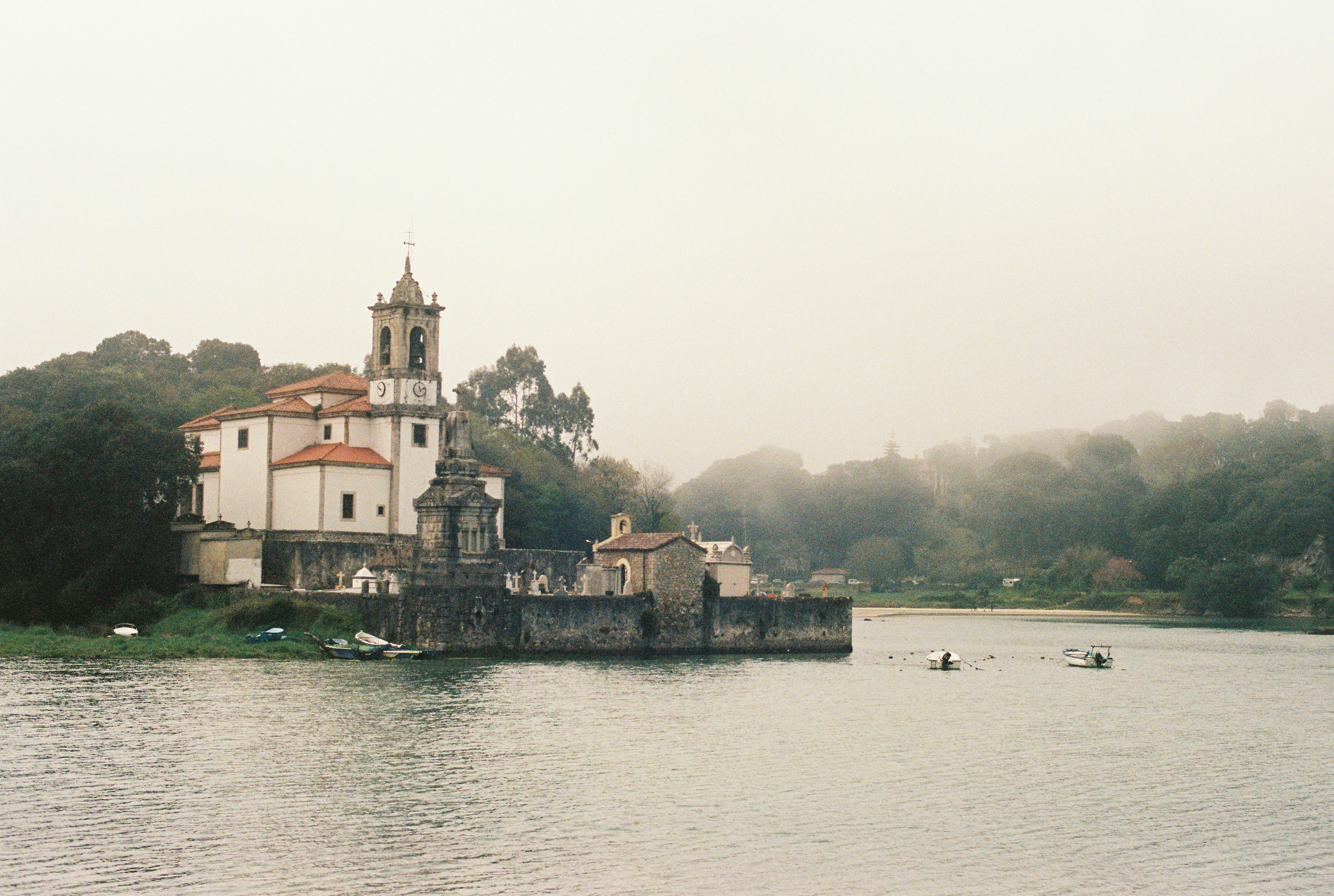Church on a lake with boats on a foggy day.