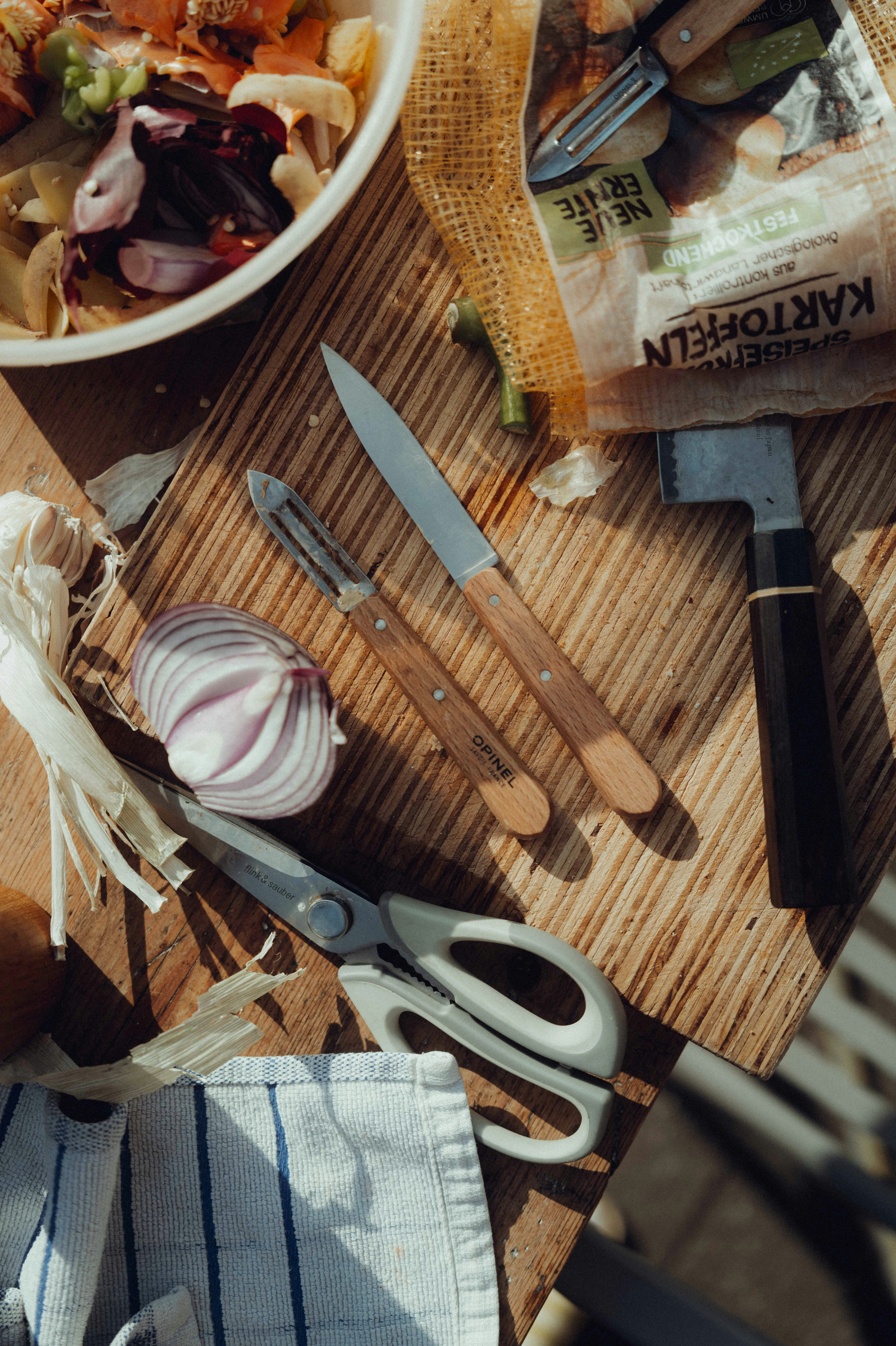 Onion, garlic, and potatoes with kitchen tools.