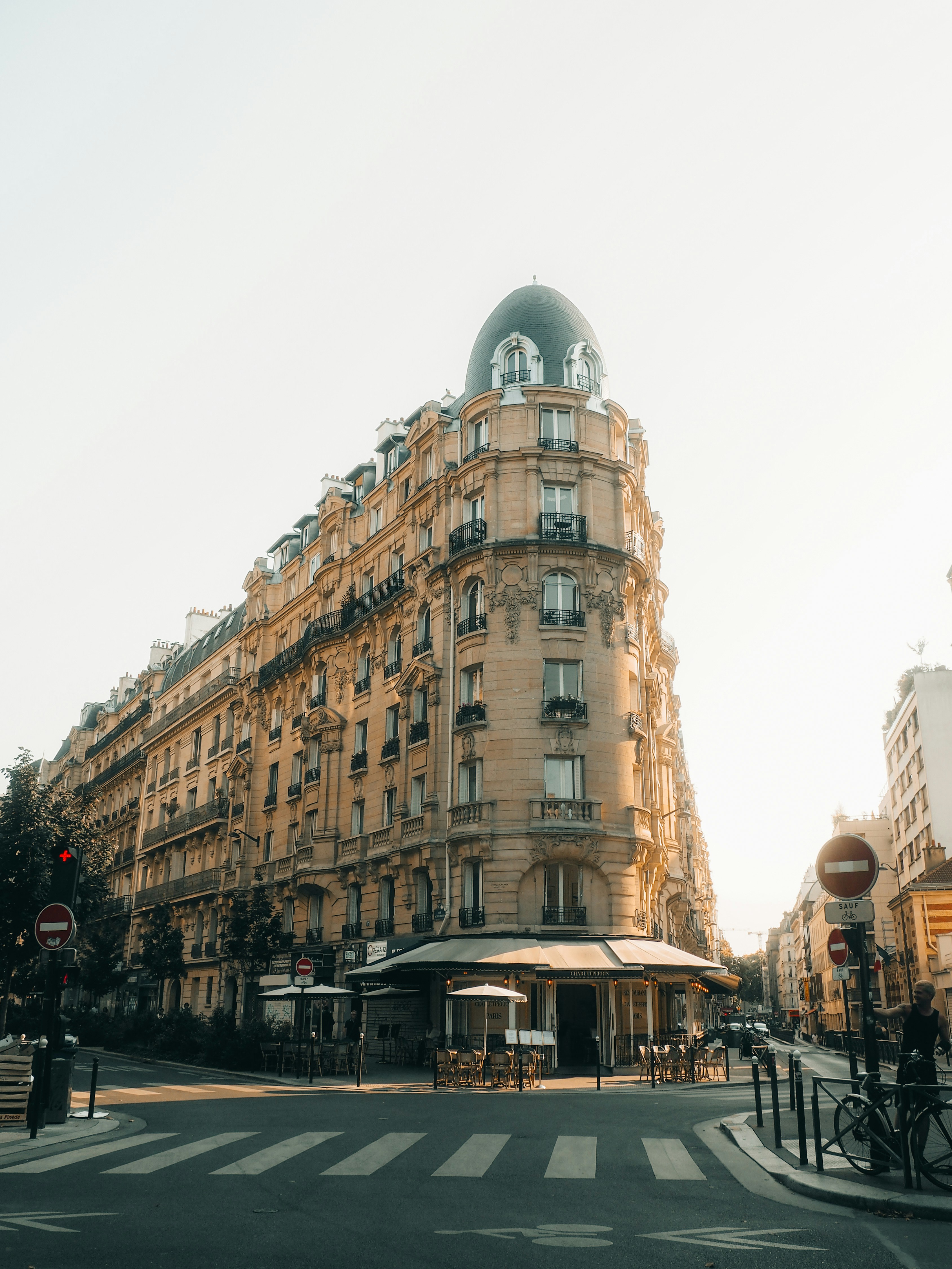 Historic building with a rounded facade and a distinctive dome, nestled at a busy intersection in a bustling city. The warm light enhances the architectural details.