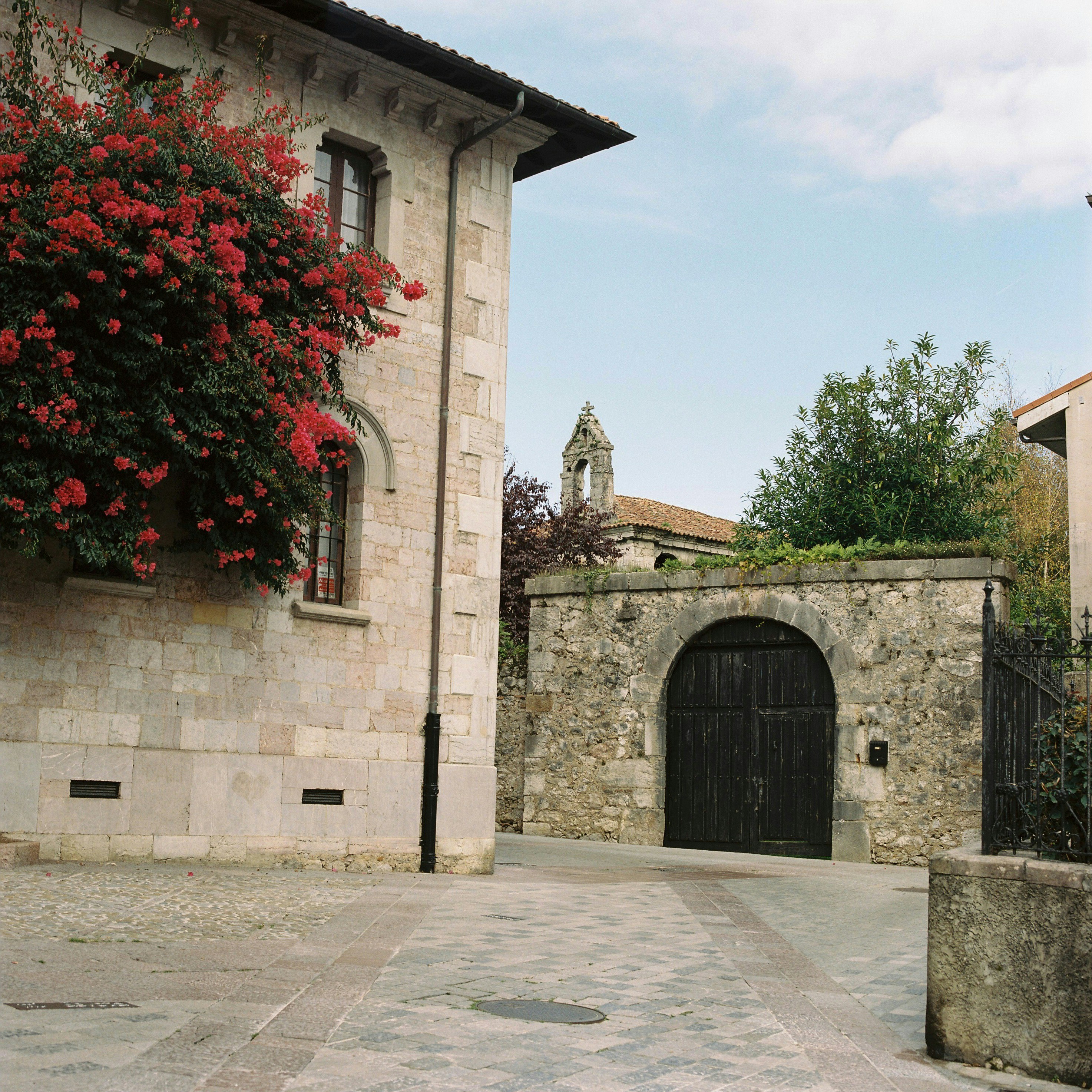 Stone building with flowering vine and arched doorway.