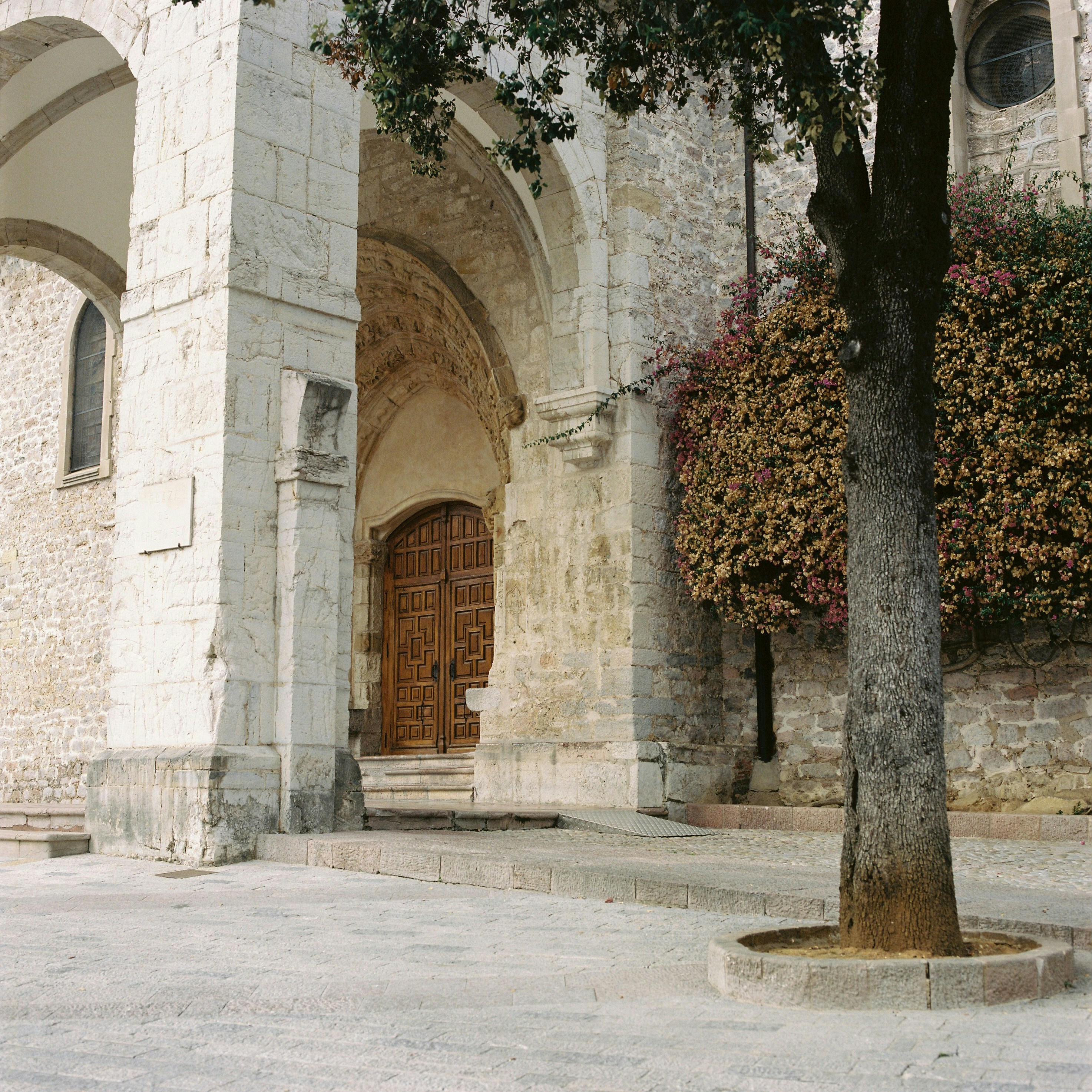 Stone building with wooden doors and a tree