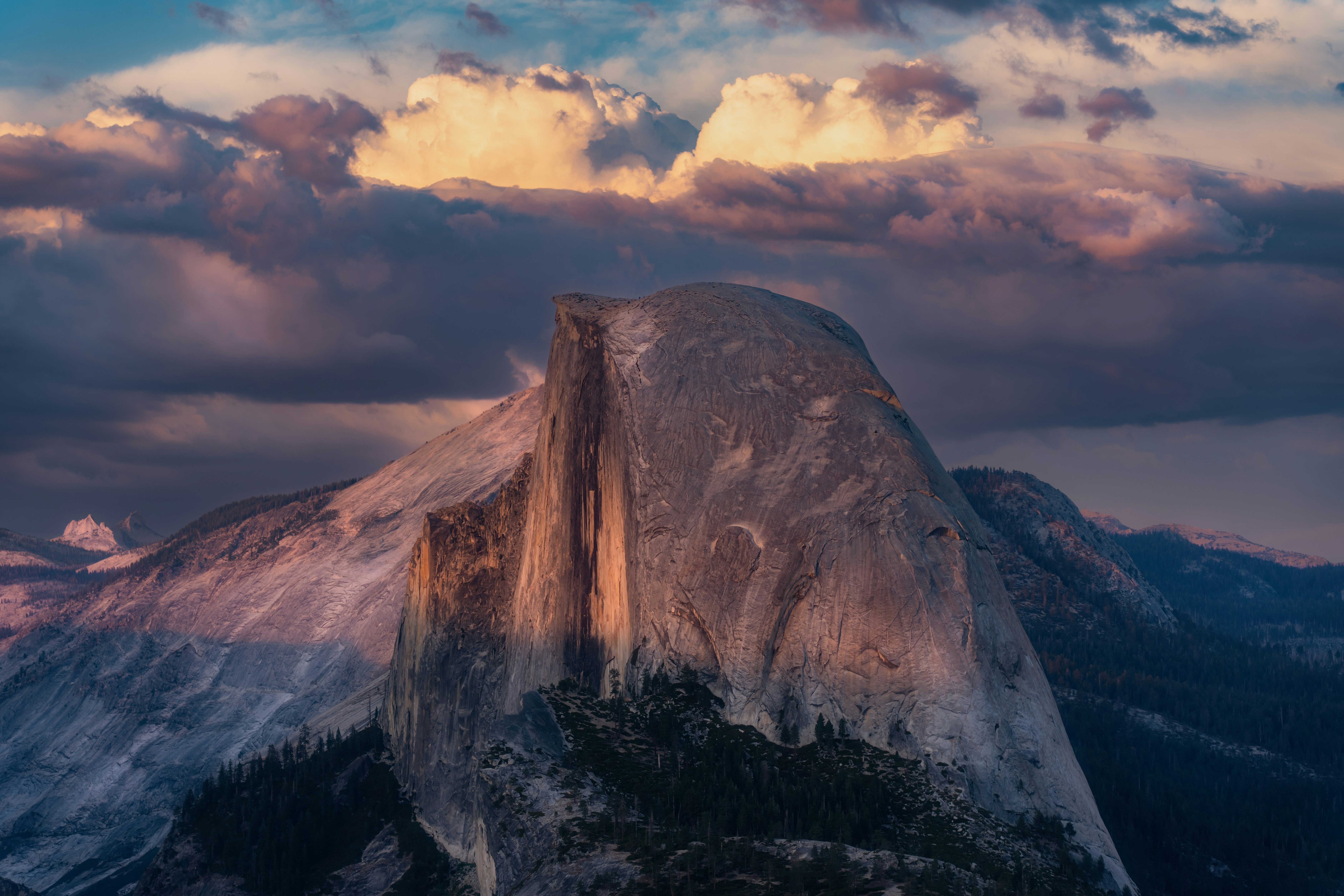Granite monolith rising dramatically against a backdrop of colorful clouds at twilight.