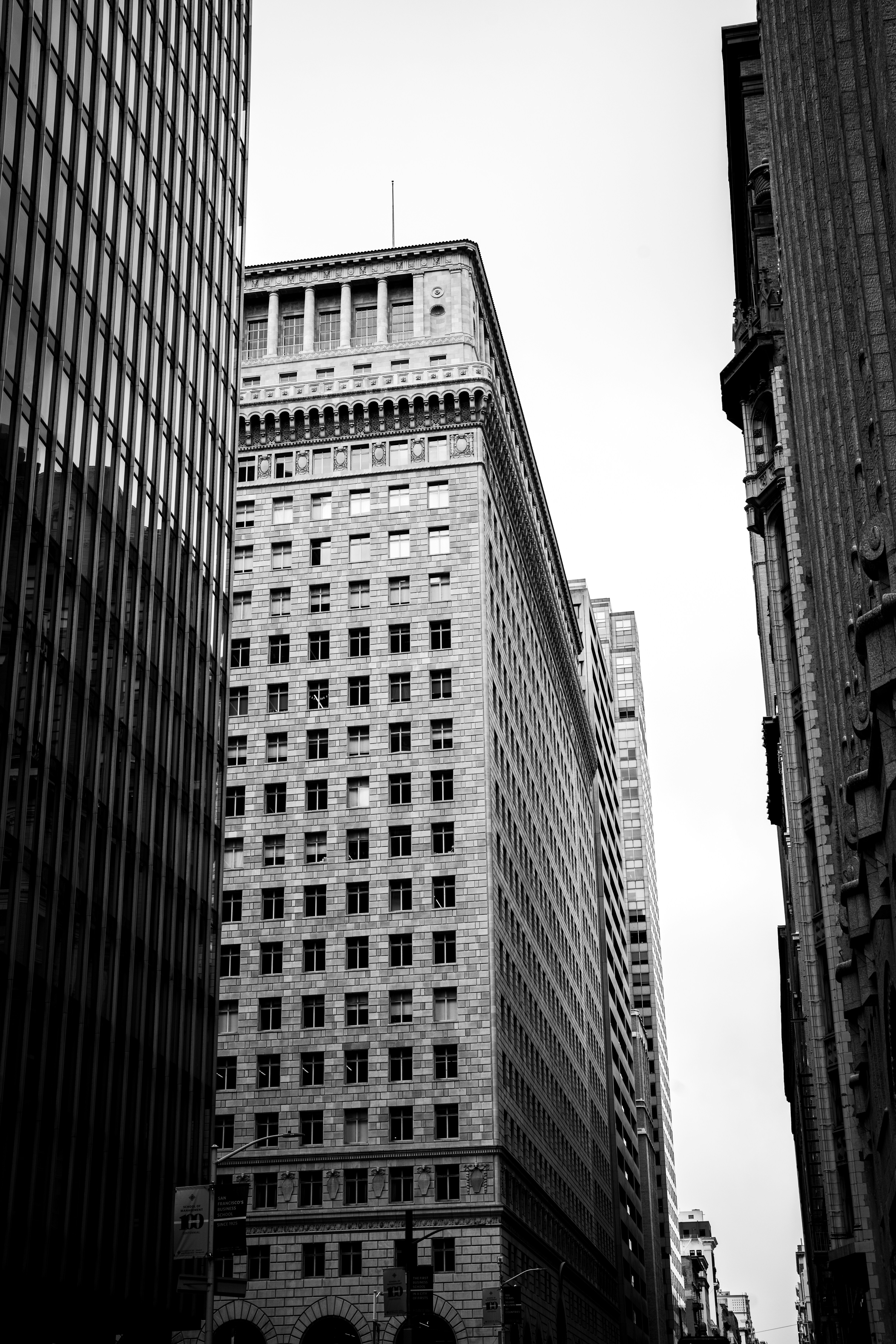 Monochrome view of towering buildings converging in a narrow street, showcasing the contrast between modern glass and classic stone structures.