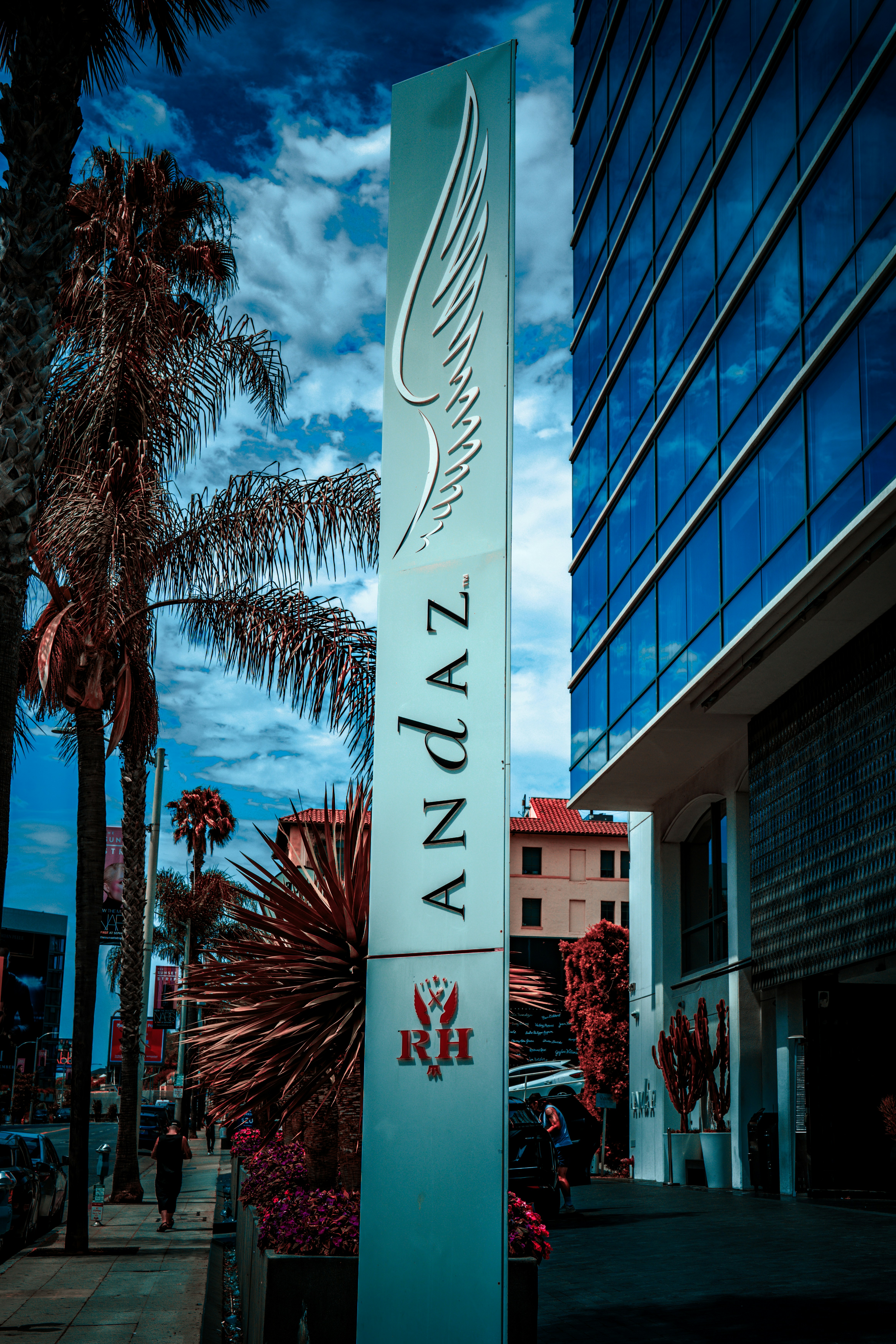 Stylish hotel signage with palm trees and modern architecture, highlighting the Andaz brand in an urban setting.