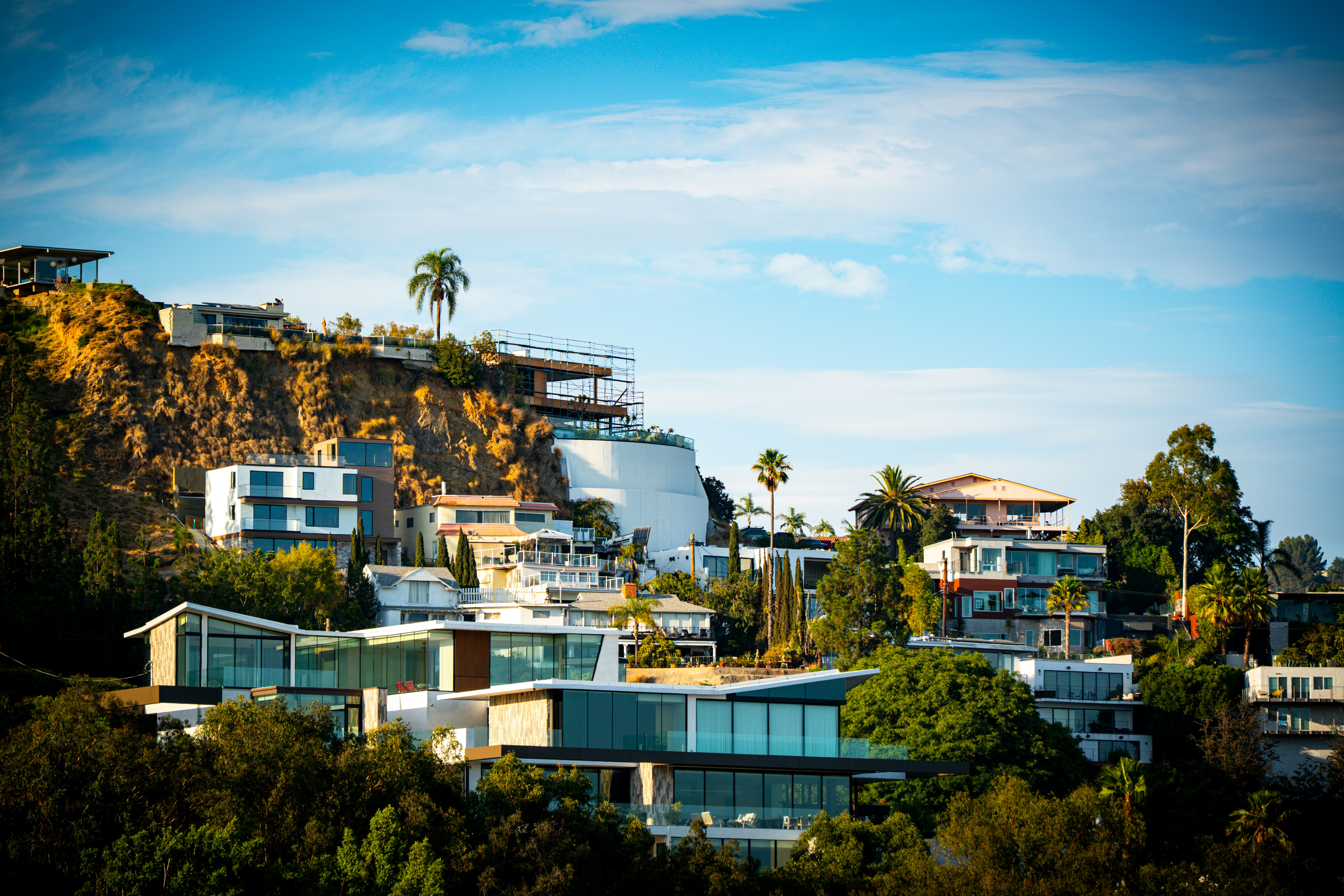 A collection of contemporary homes nestled against a hillside, showcasing diverse architectural styles and lush greenery.