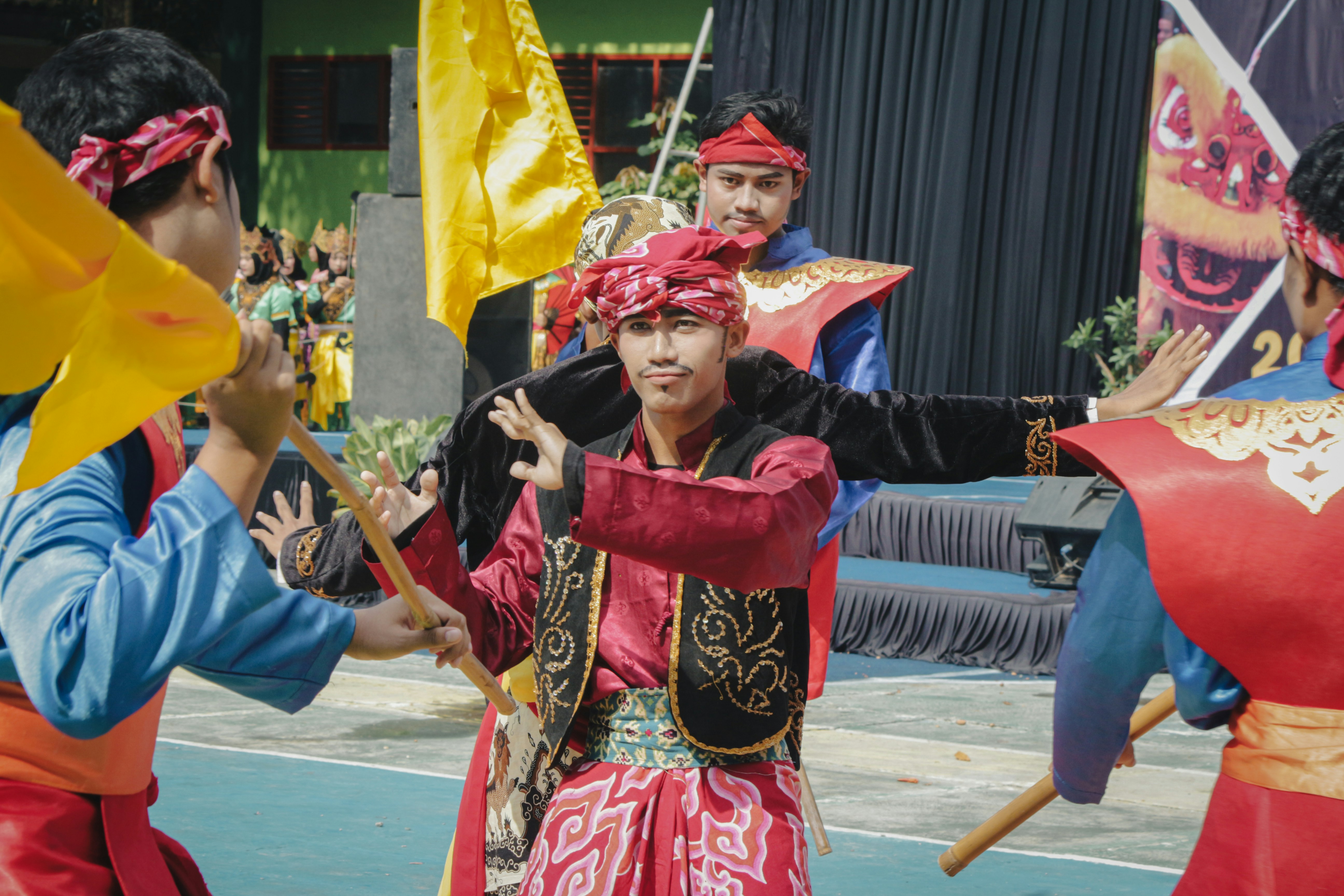 Performers in vibrant traditional costumes engage in a dynamic dance, showcasing cultural heritage with flags and expressive gestures.