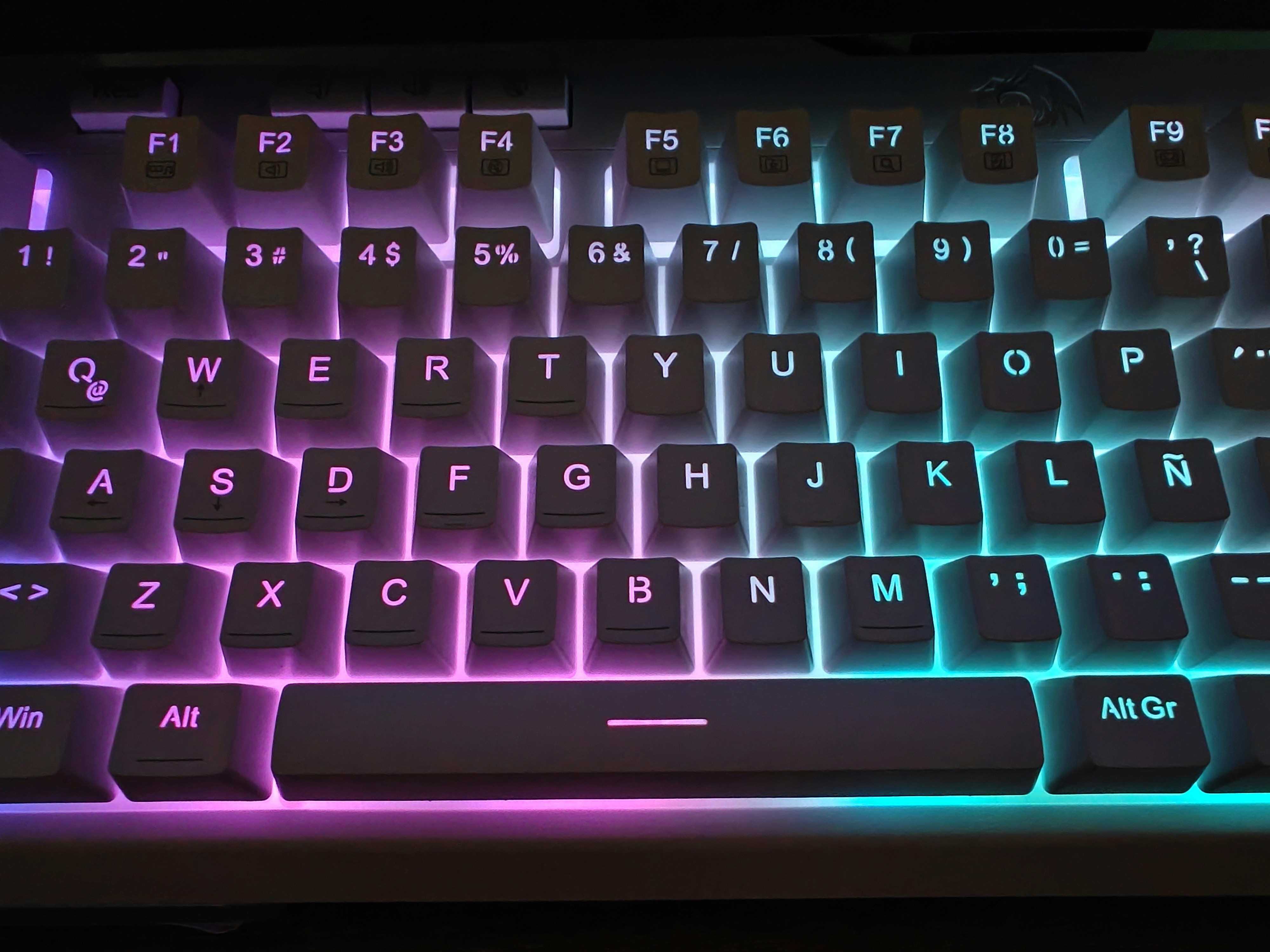 Illuminated keyboard showcasing vibrant RGB lighting with a focus on the QWERTY layout and gaming keys. The design highlights the modern aesthetic of gaming peripherals.