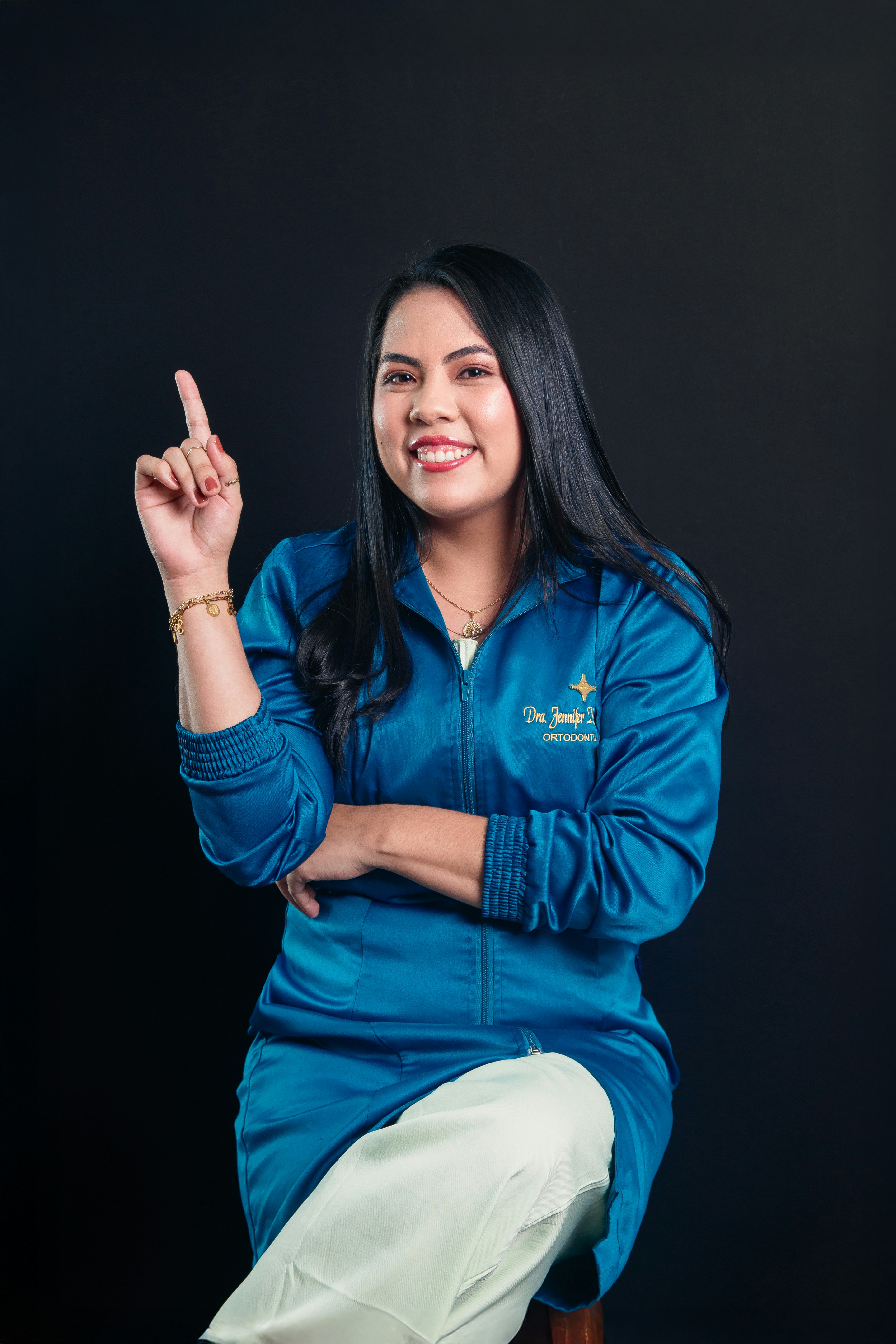 Woman in blue lab coat points finger upwards