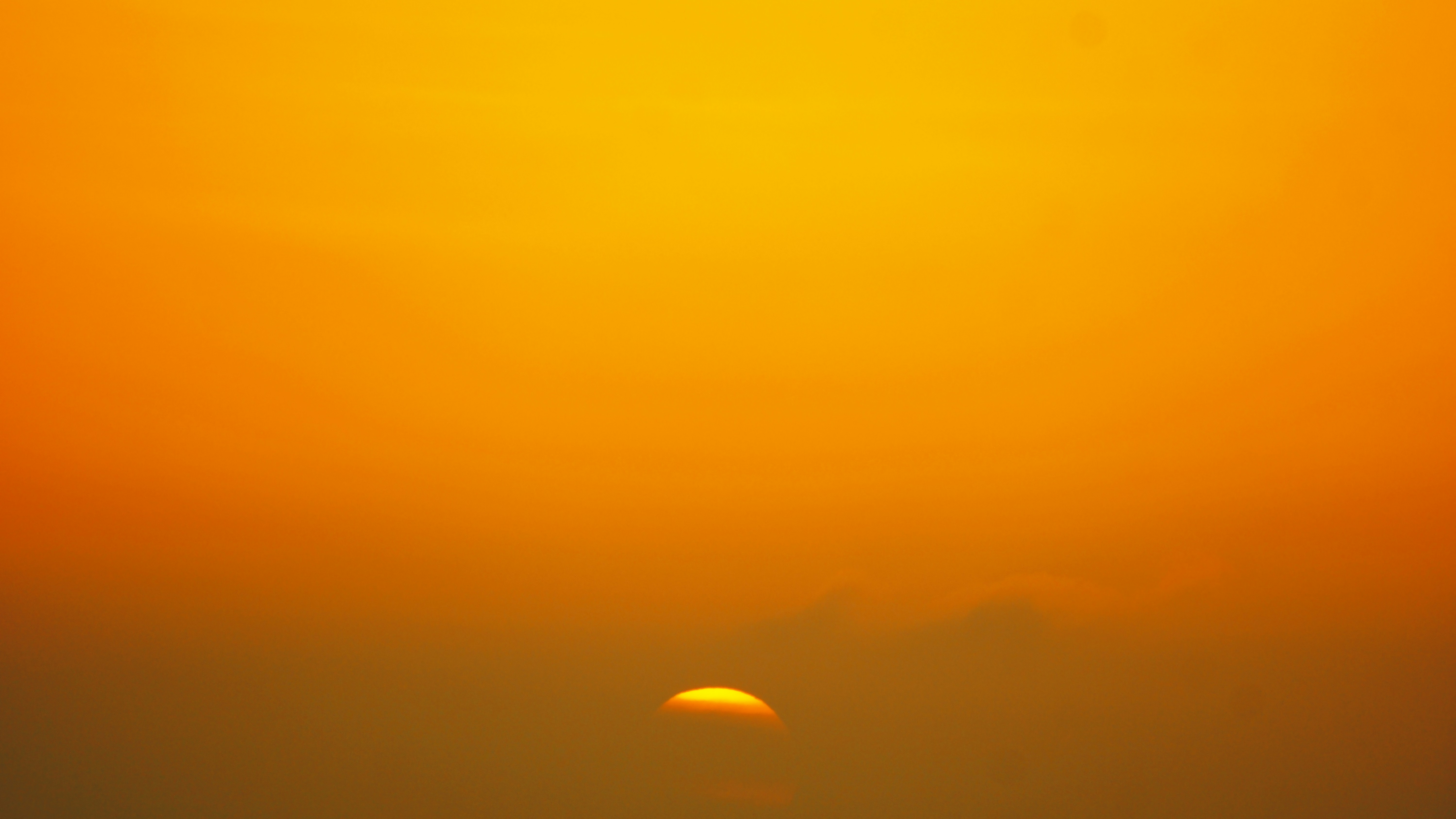 A bright orange sky with a setting sun.