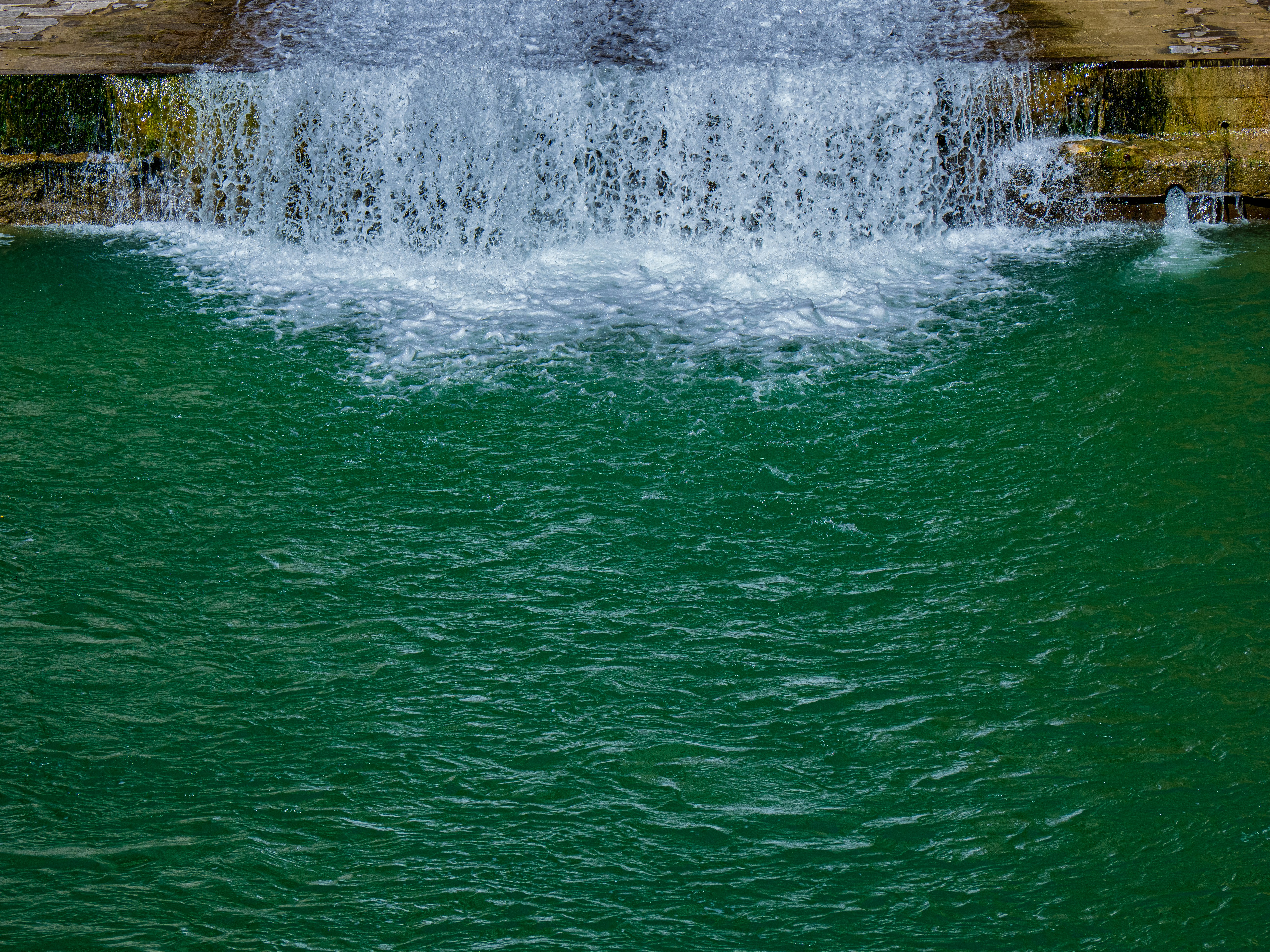 A cascading waterfall flows into a clear green pool. photo – Free ...