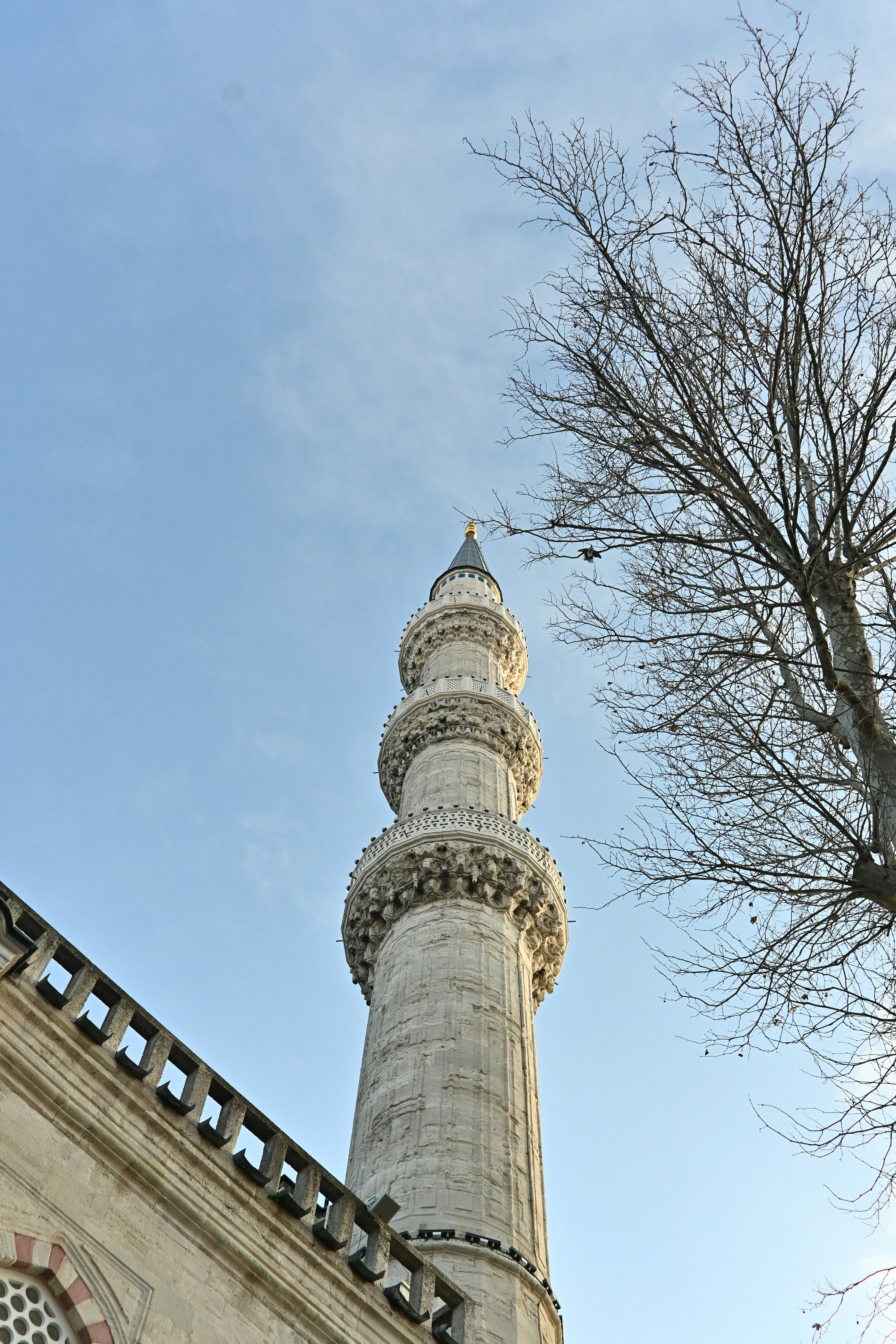 A tall, ornate minaret against a clear blue sky.
