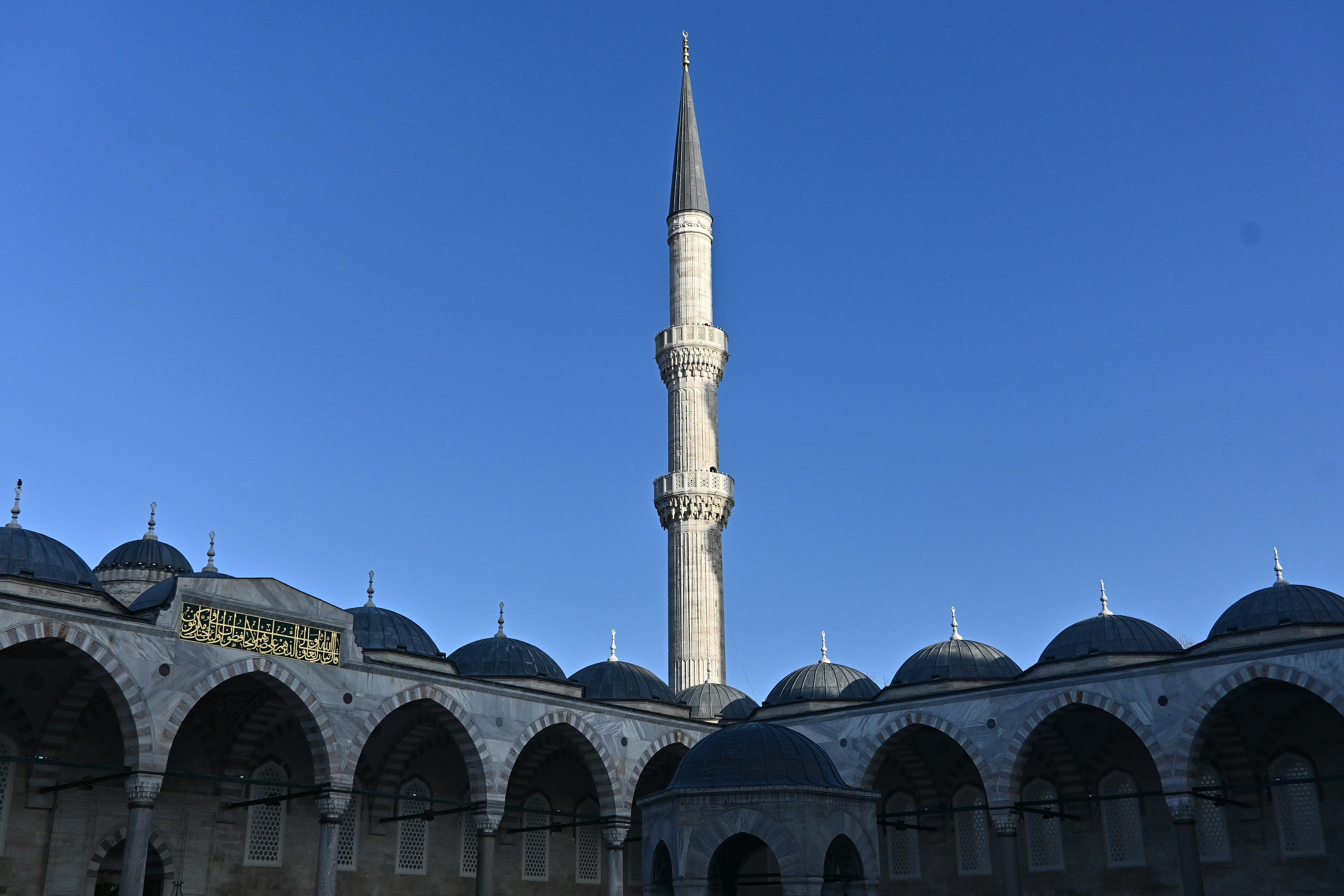 A tall minaret rises above a mosque courtyard.