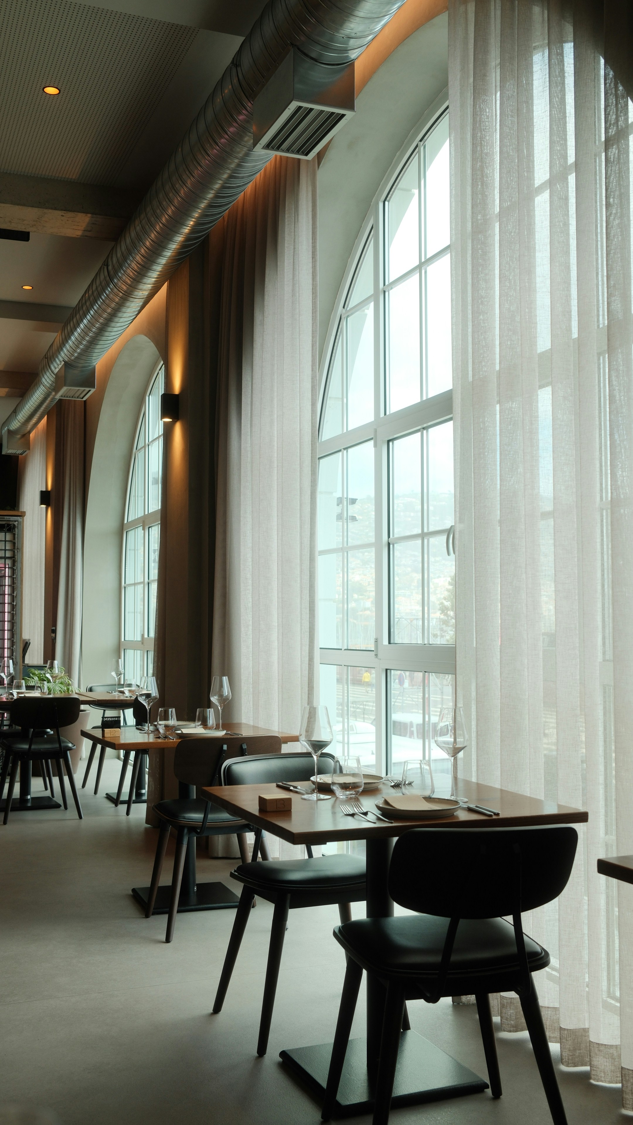 Cozy restaurant interior | Modern restaurant interior with tables and large arched windows.