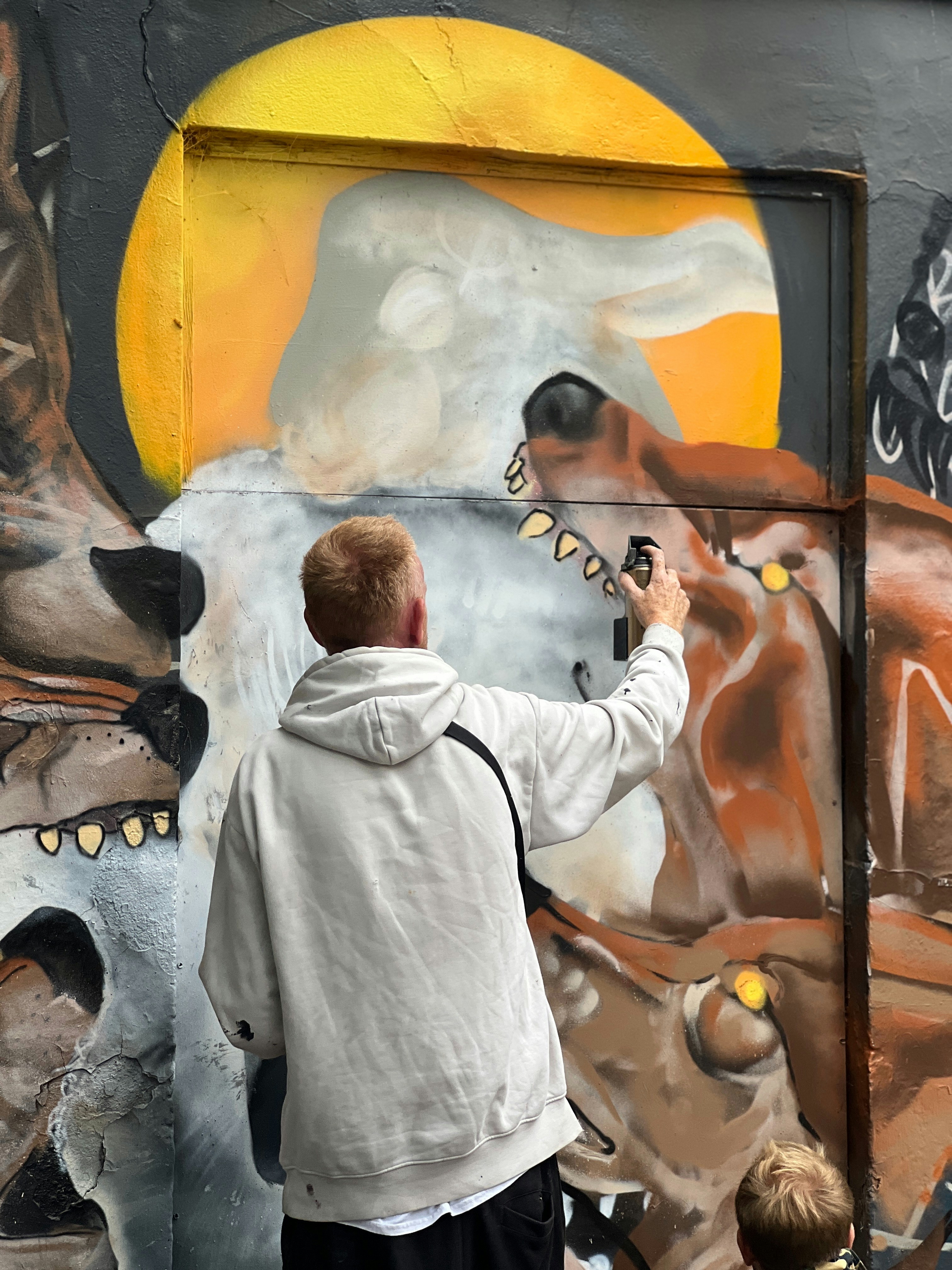 Mid-gesture aerosol: a street artist reshaping a dragon mural
