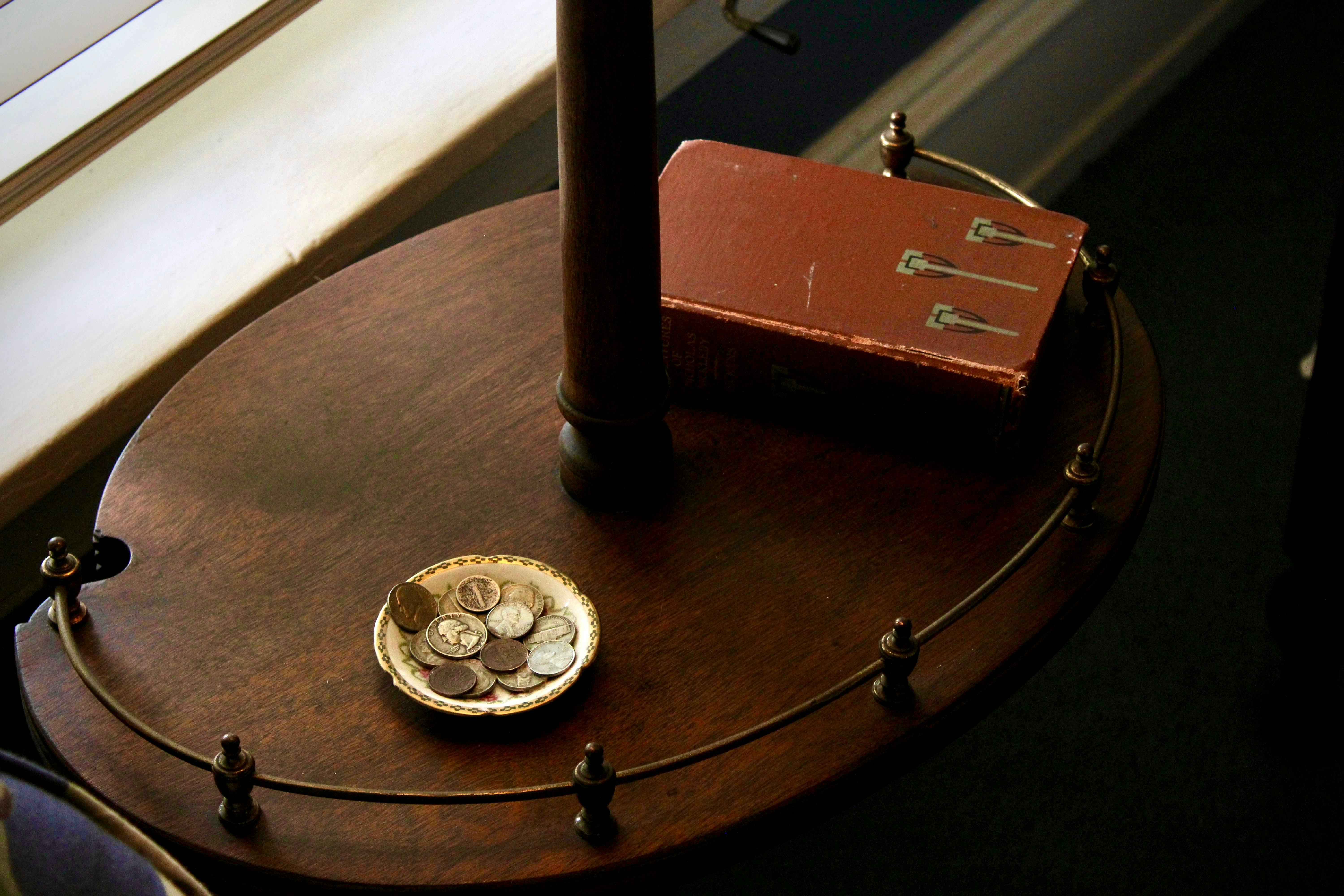 A red book and coins on a wooden table.