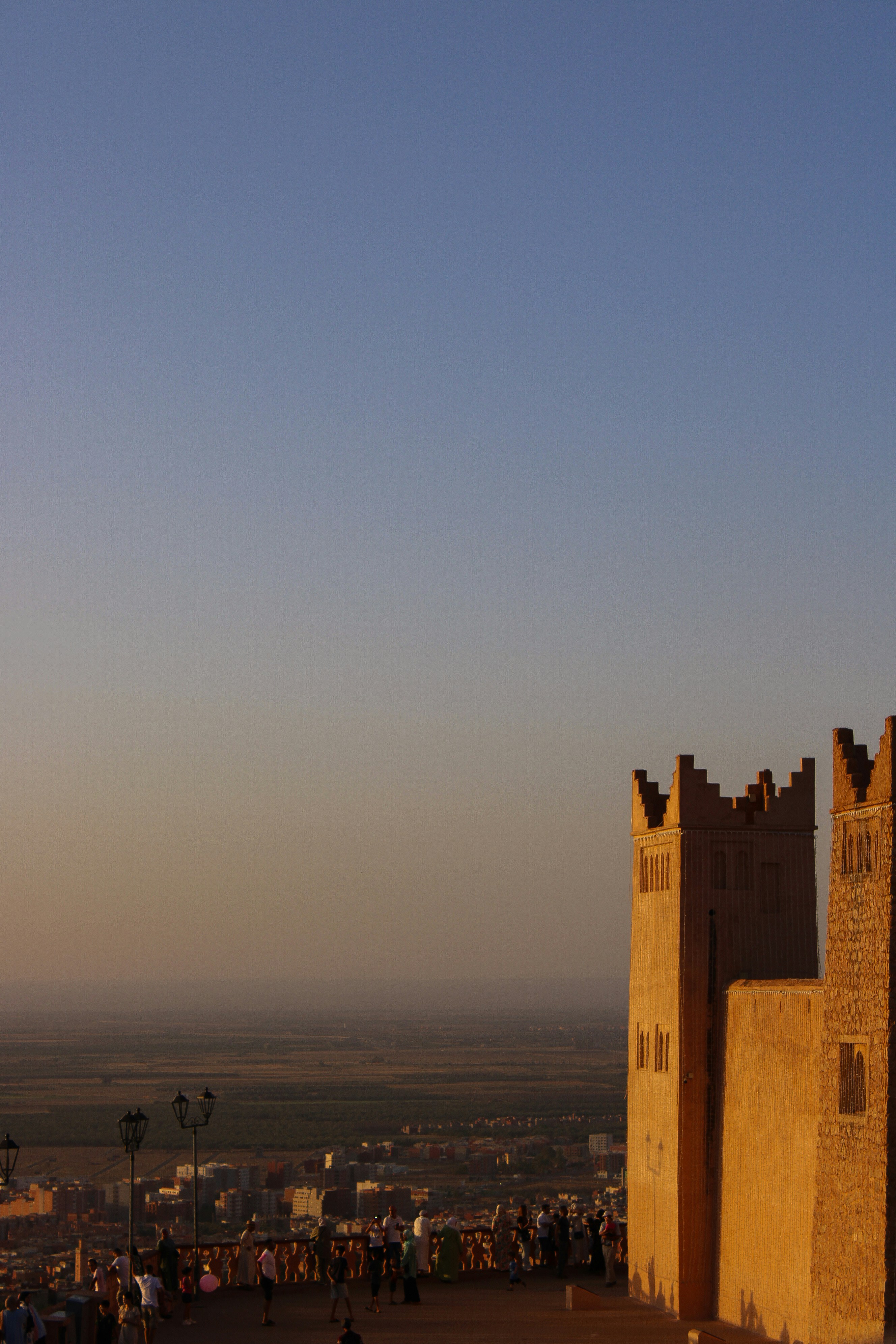 Historic towers silhouetted against a golden sunset, with visitors enjoying the panoramic view. 