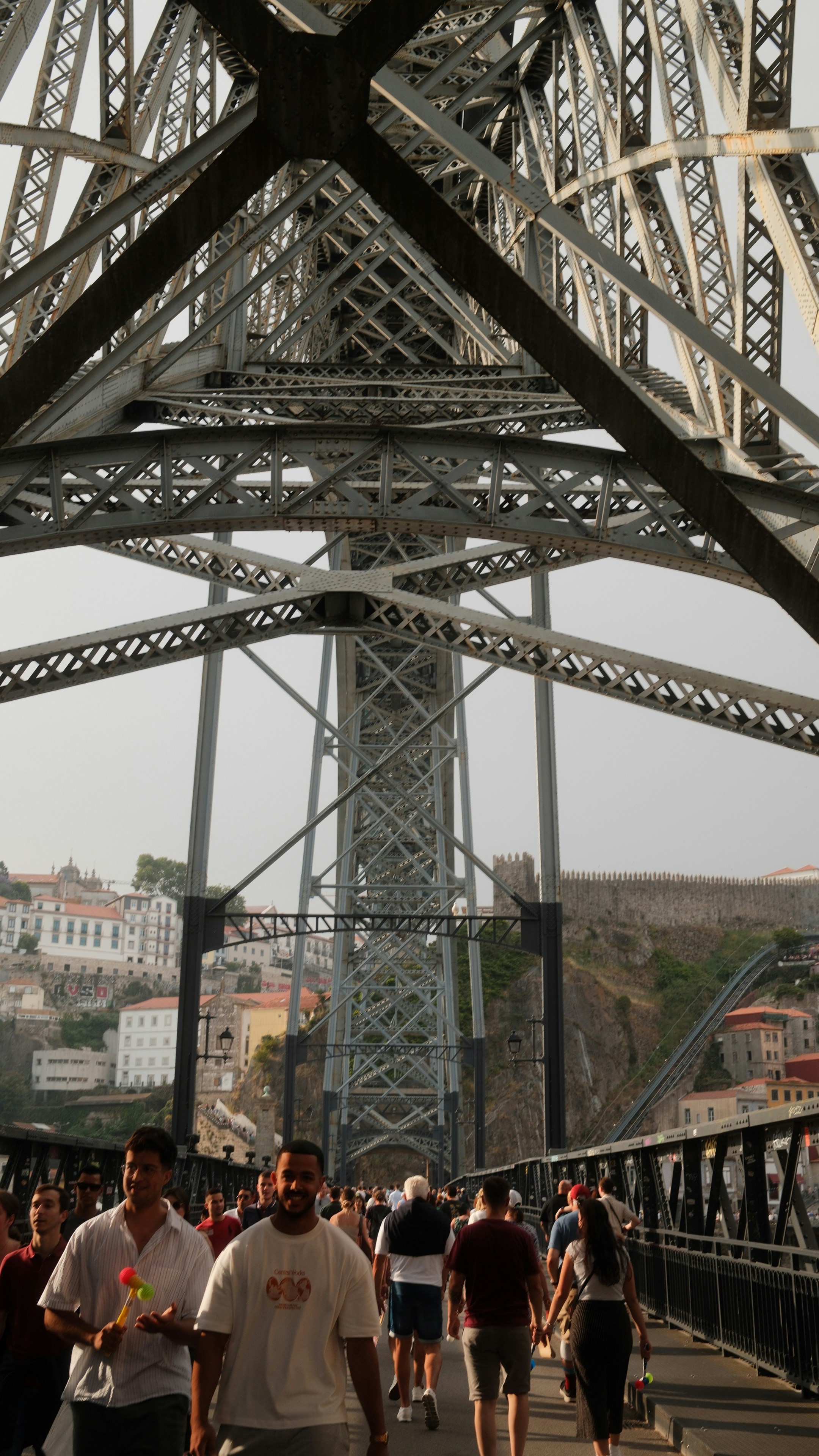 People walking on a bridge with intricate metal structure.