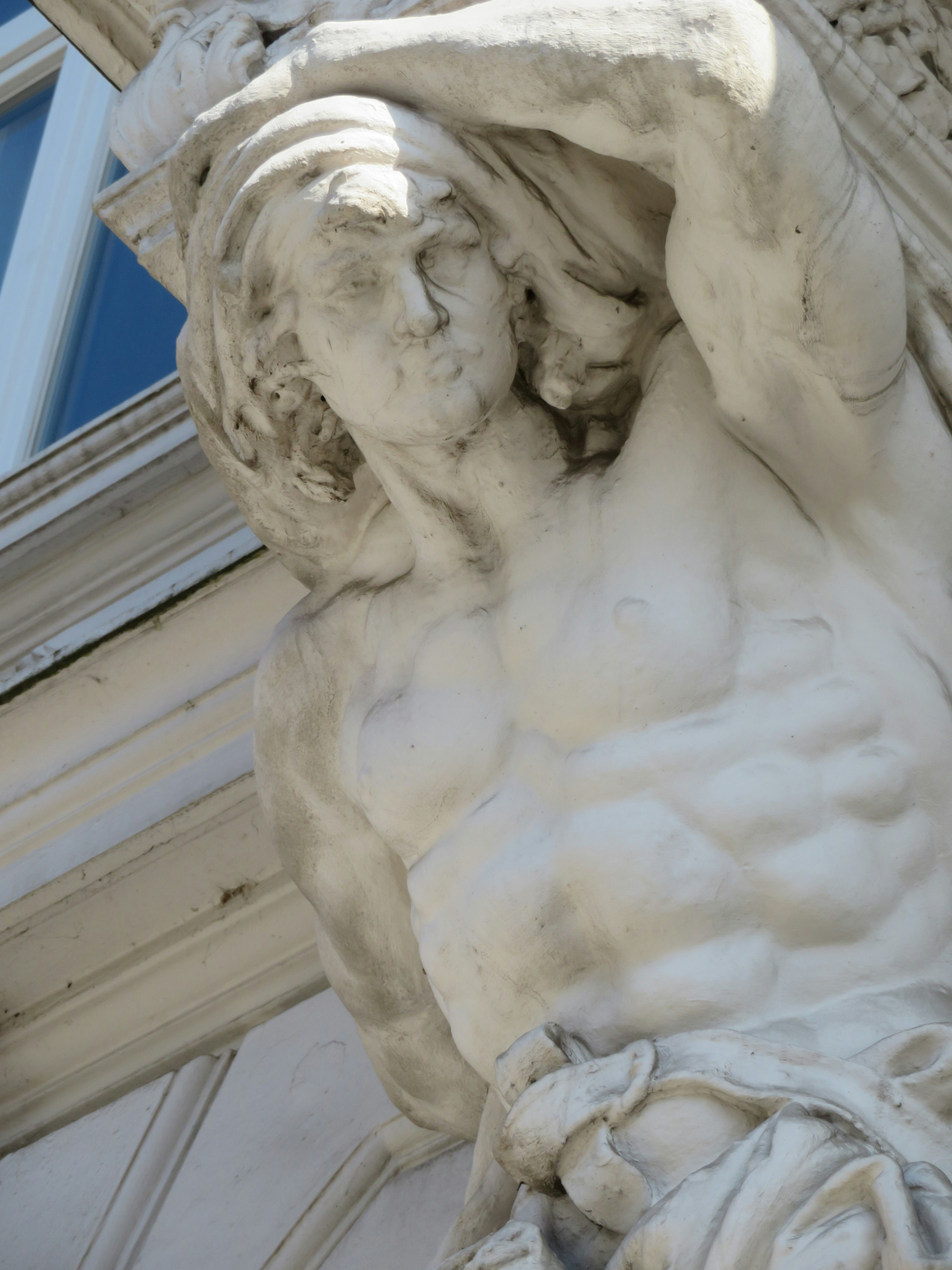 Stone sculpture of a muscular man holding weight