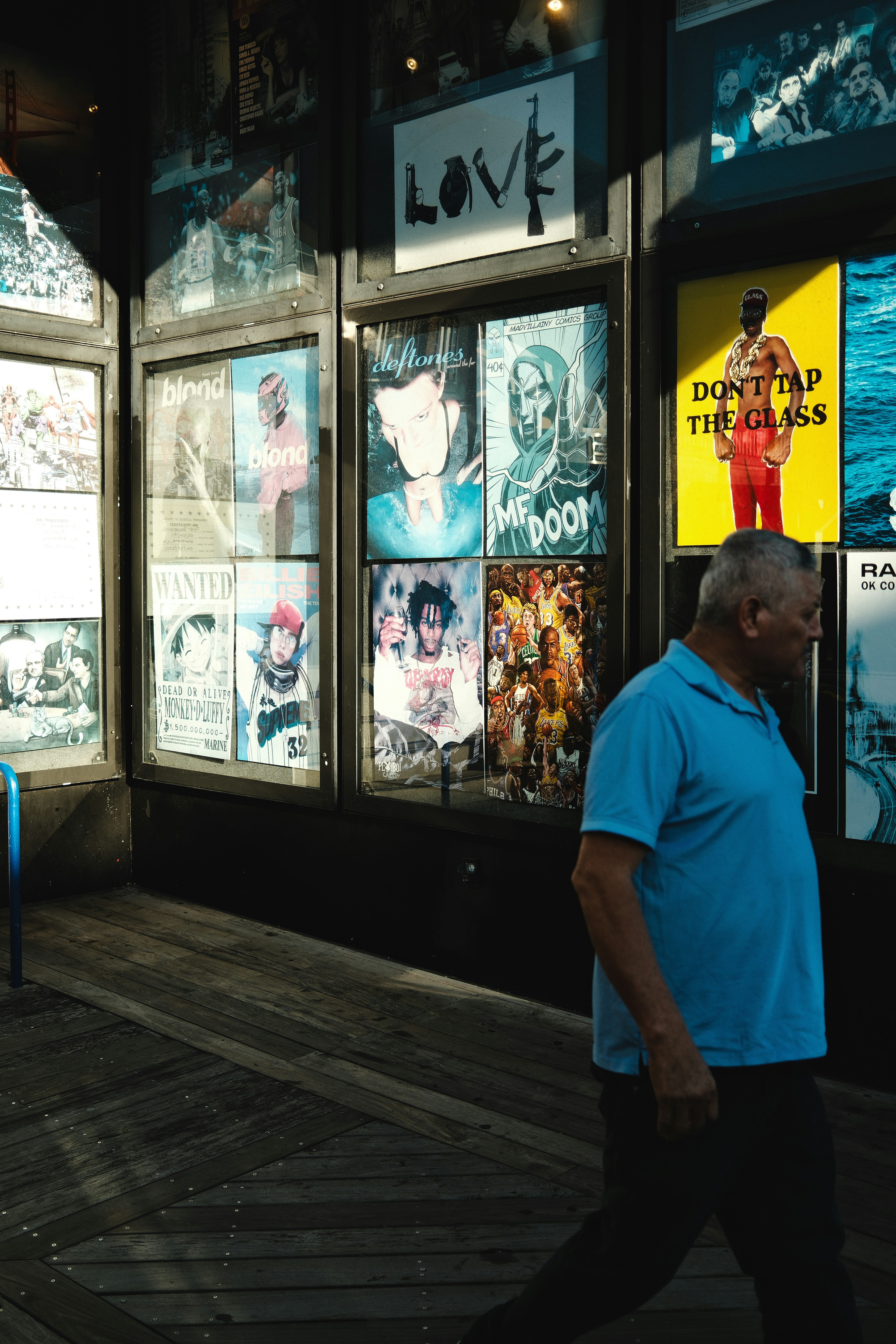 Man walks past posters in a display case.