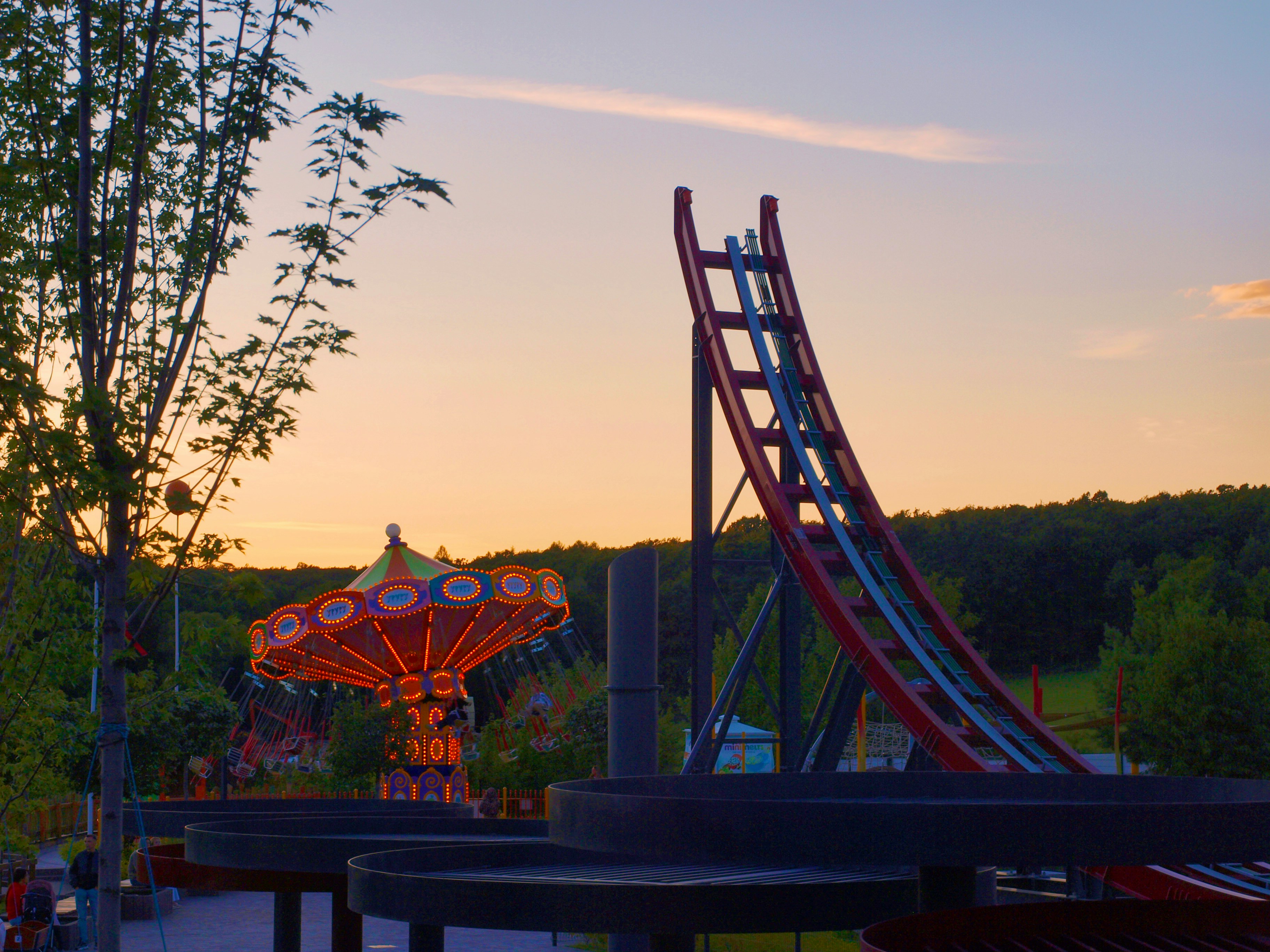 Amusement park rides at sunset with roller coaster