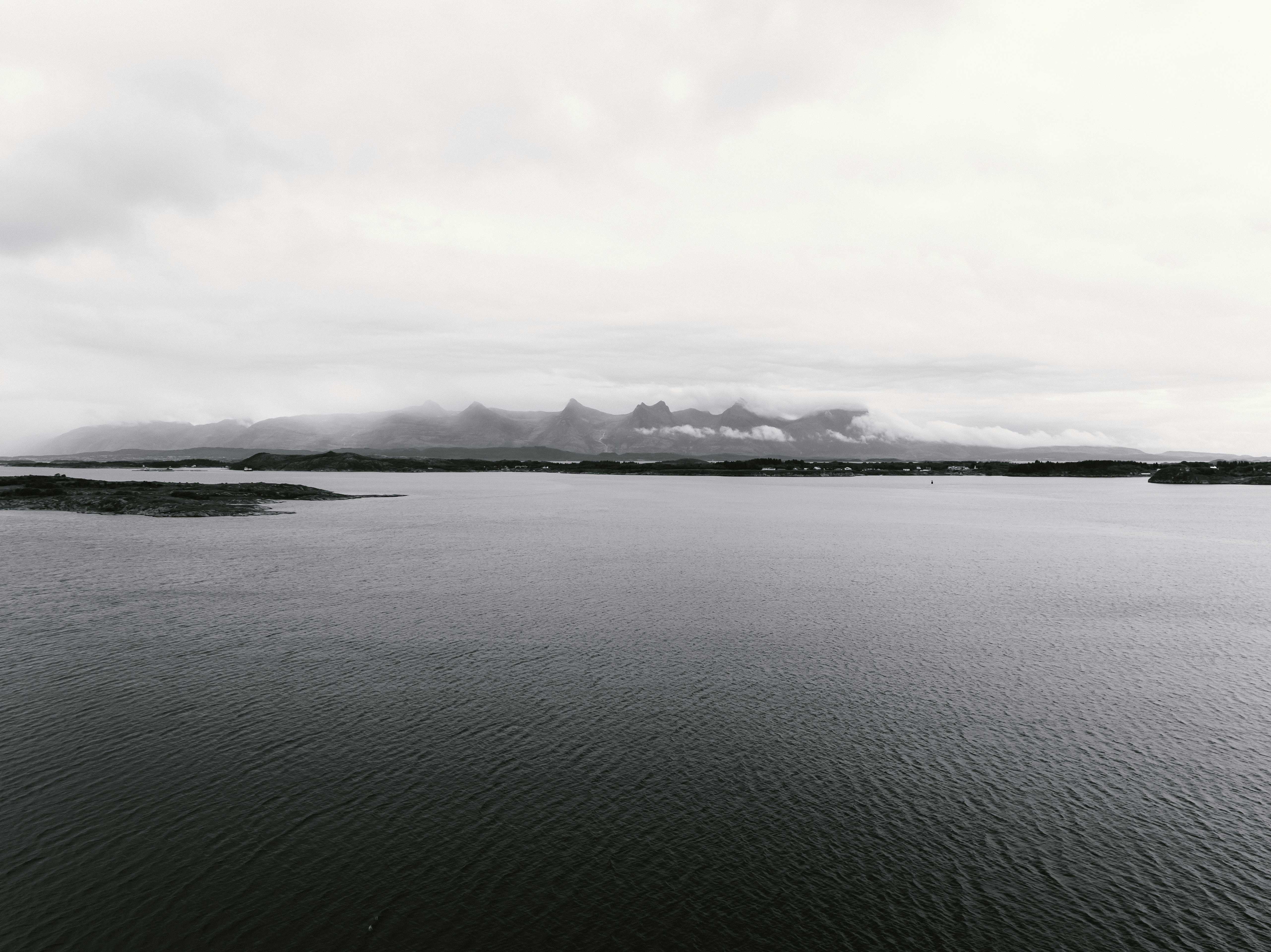 Misty mountains over a calm body of water