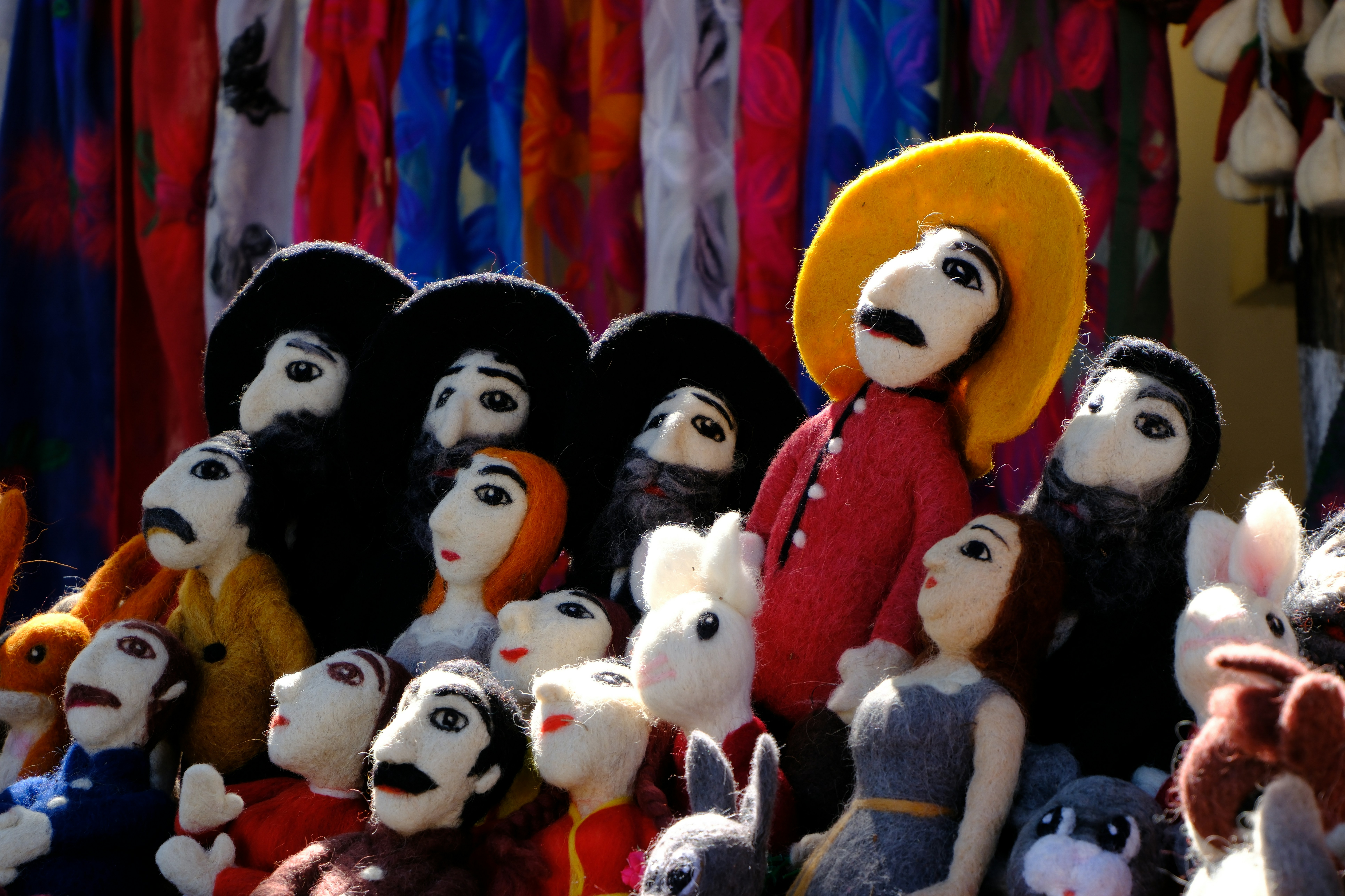 A vibrant display of handcrafted felt puppets, showcasing diverse expressions and attire against a colorful backdrop. Each character tells a unique story.