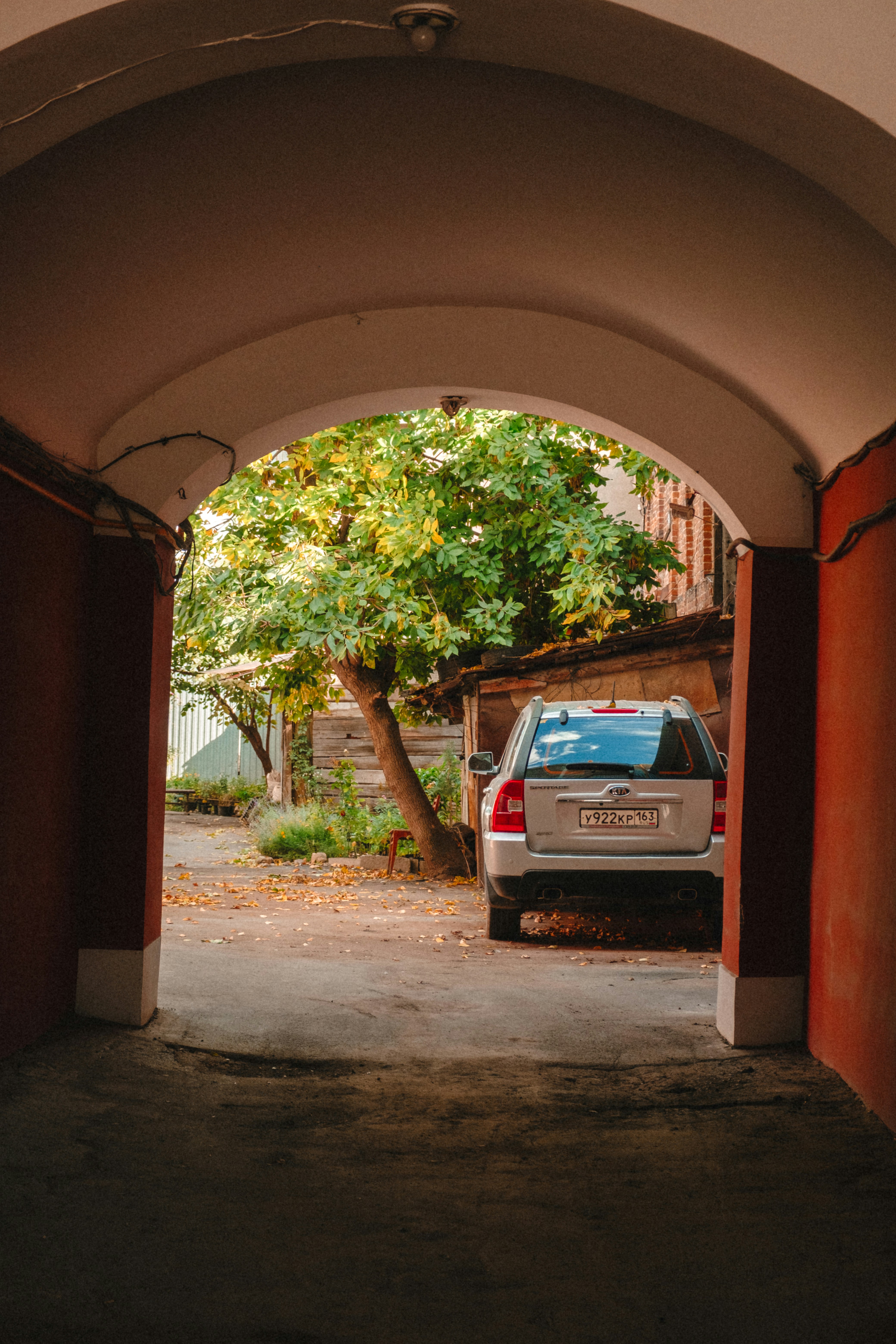 Silver car parked in a courtyard through an archway