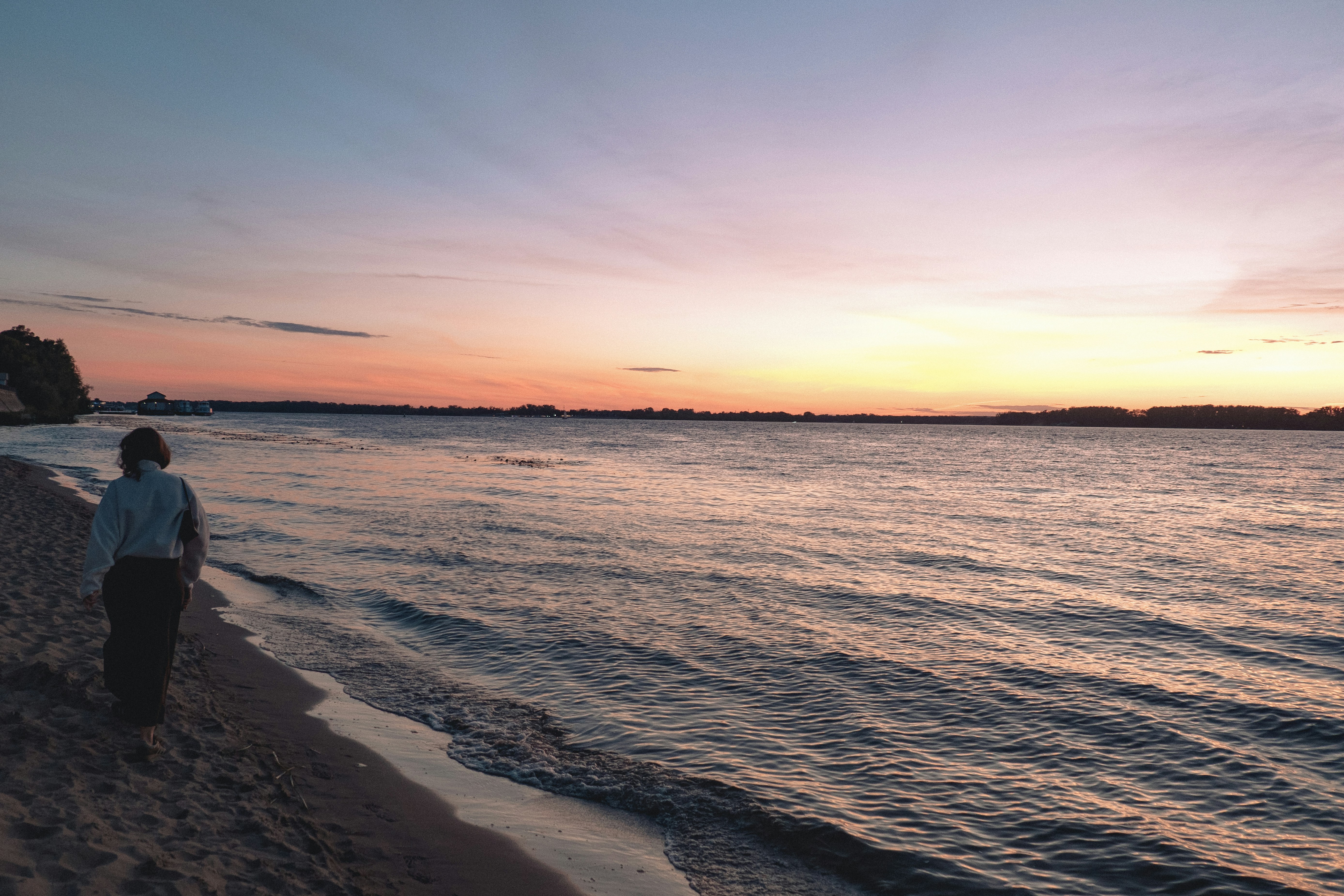 Person walking on a beach at sunset